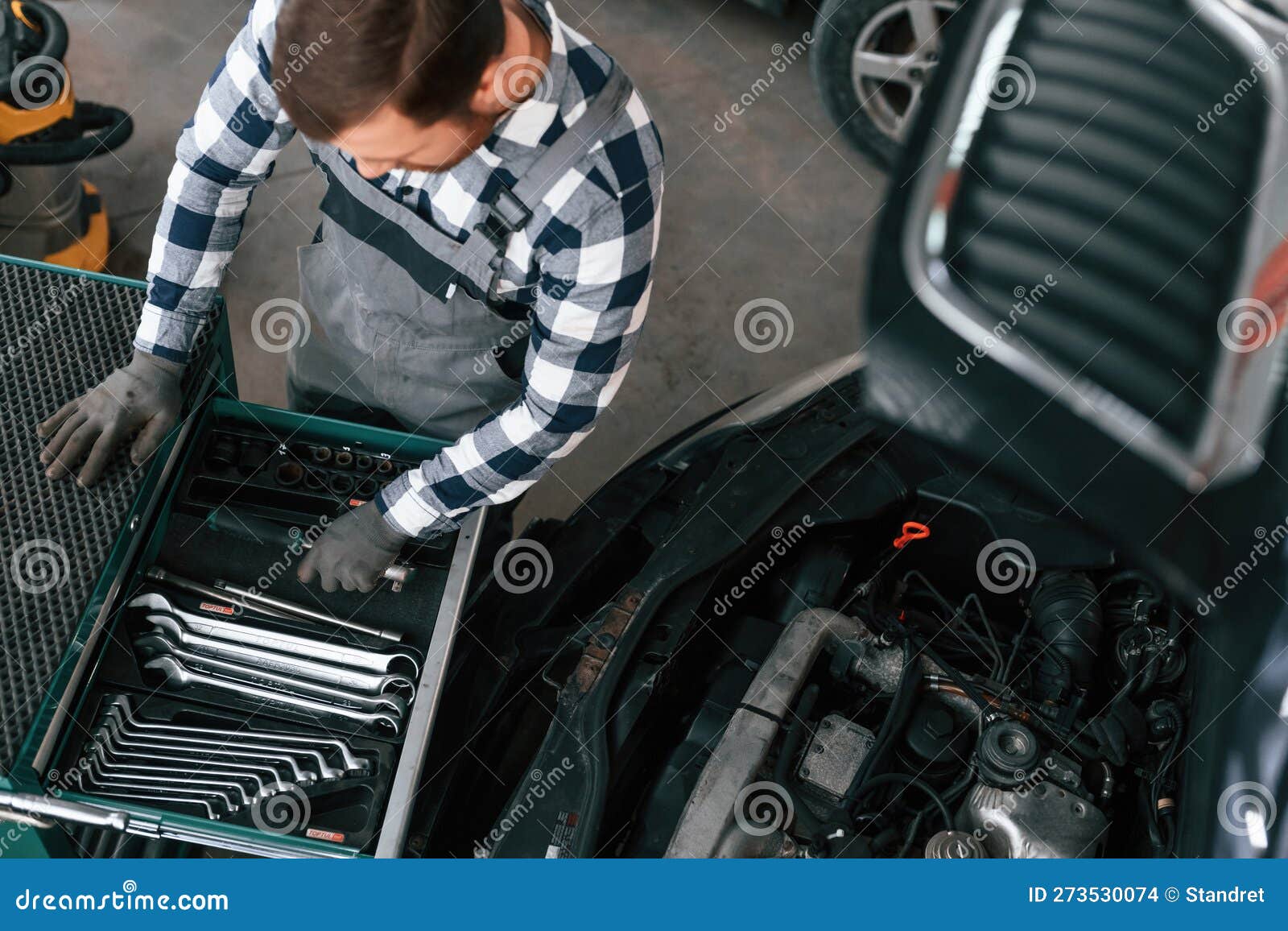 Using the Tool and Fixing the Car. Man in Uniform is Working in the ...