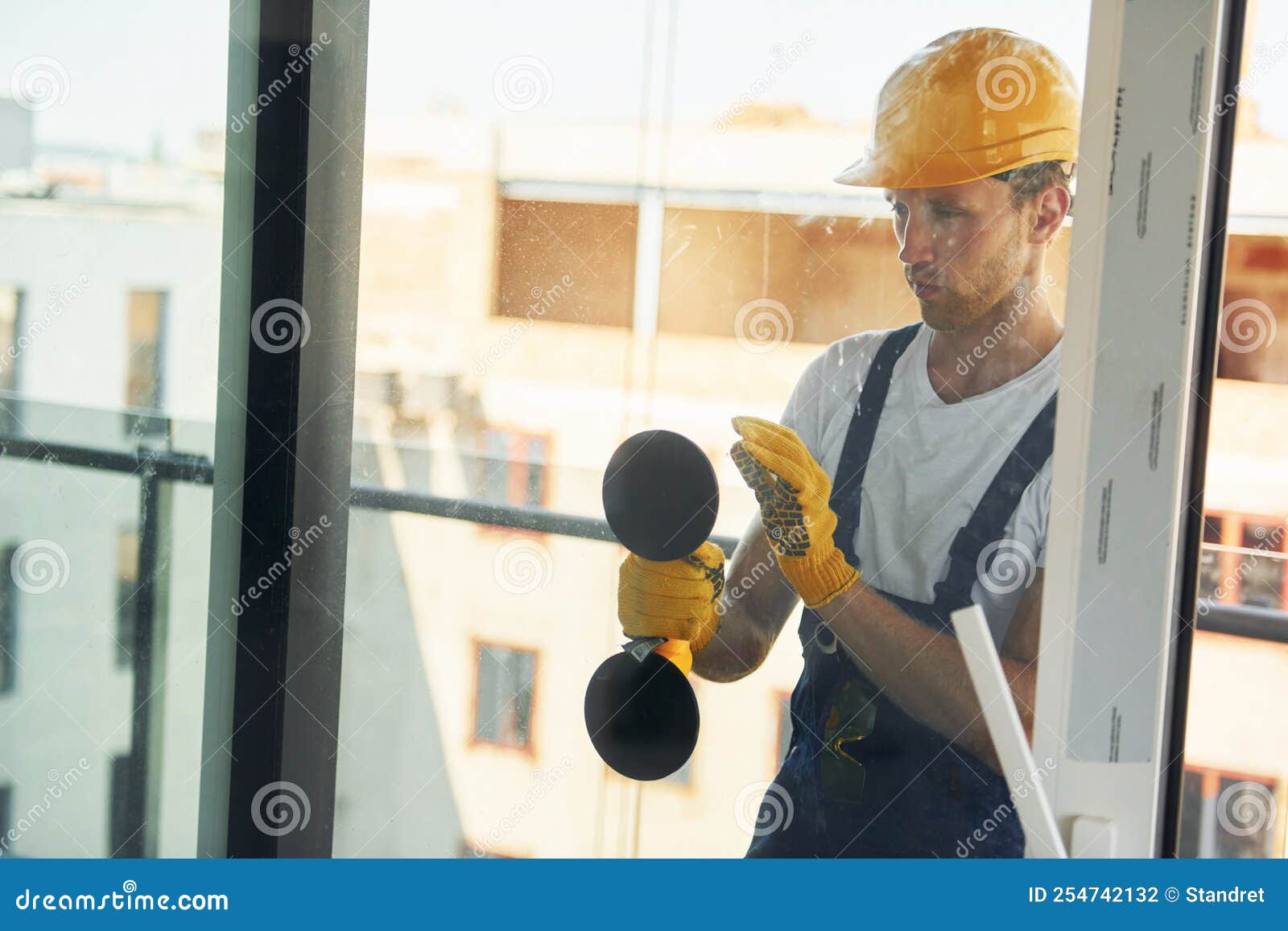 Using Tool on Glass. Young Man Working in Uniform at Construction at ...