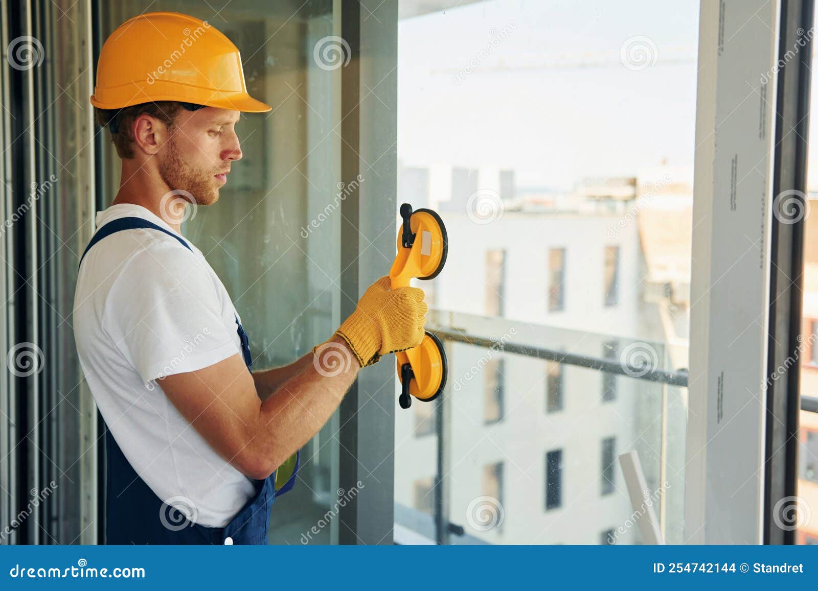 Using Tool on Glass. Young Man Working in Uniform at Construction at ...