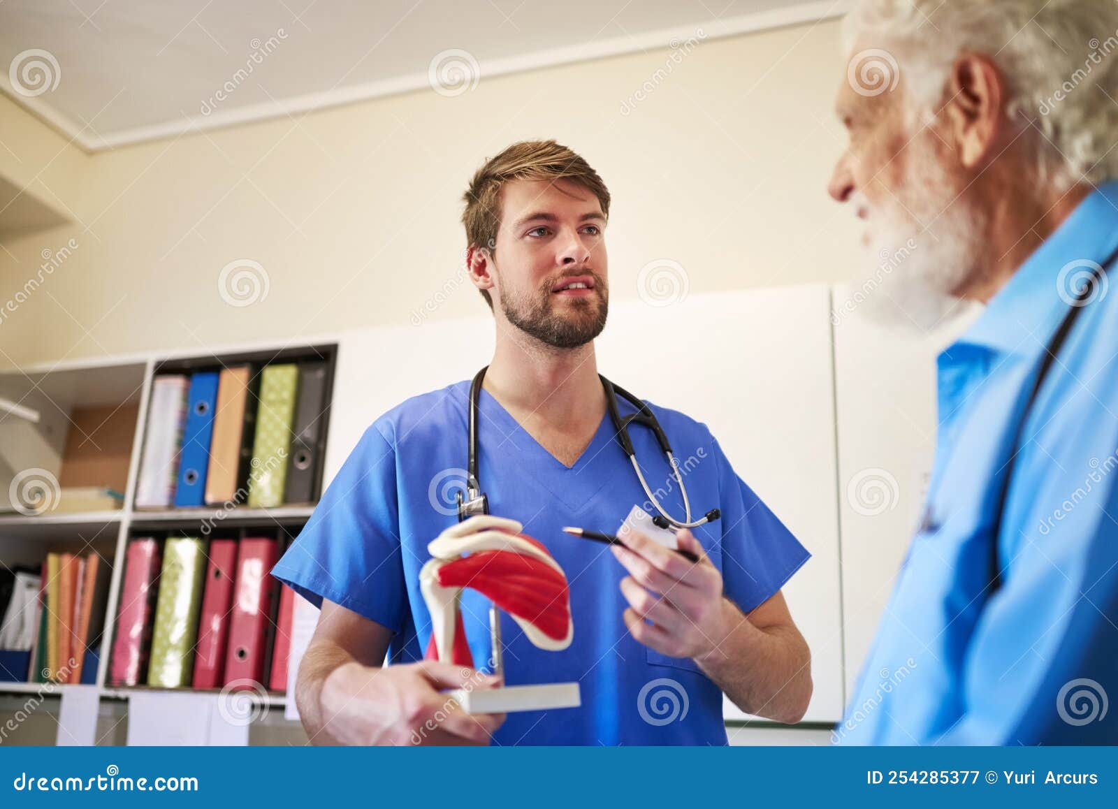 Using Visuals To Help Him Understand. a Young Doctor Using a Model To ...