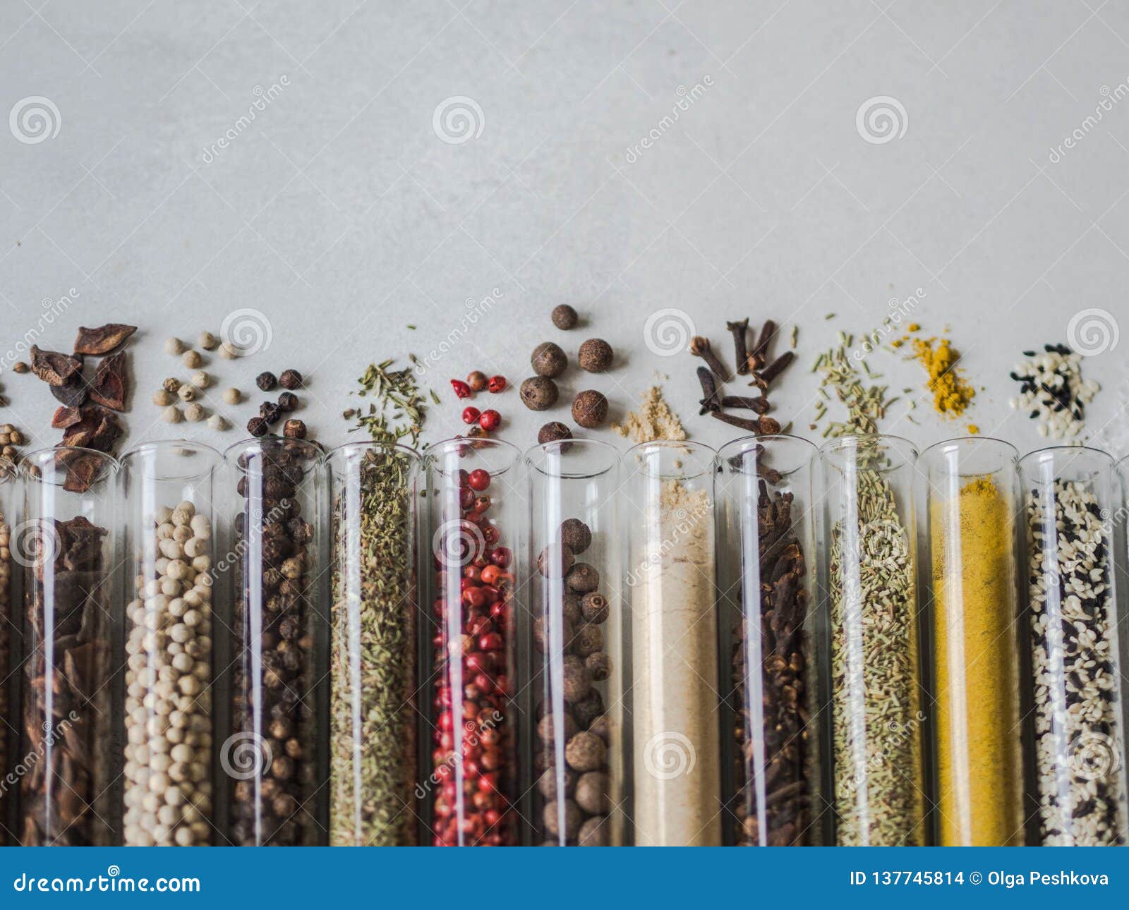 Various Dry Spices in Glass Tubes and Spilled on Gray Background. Copy ...