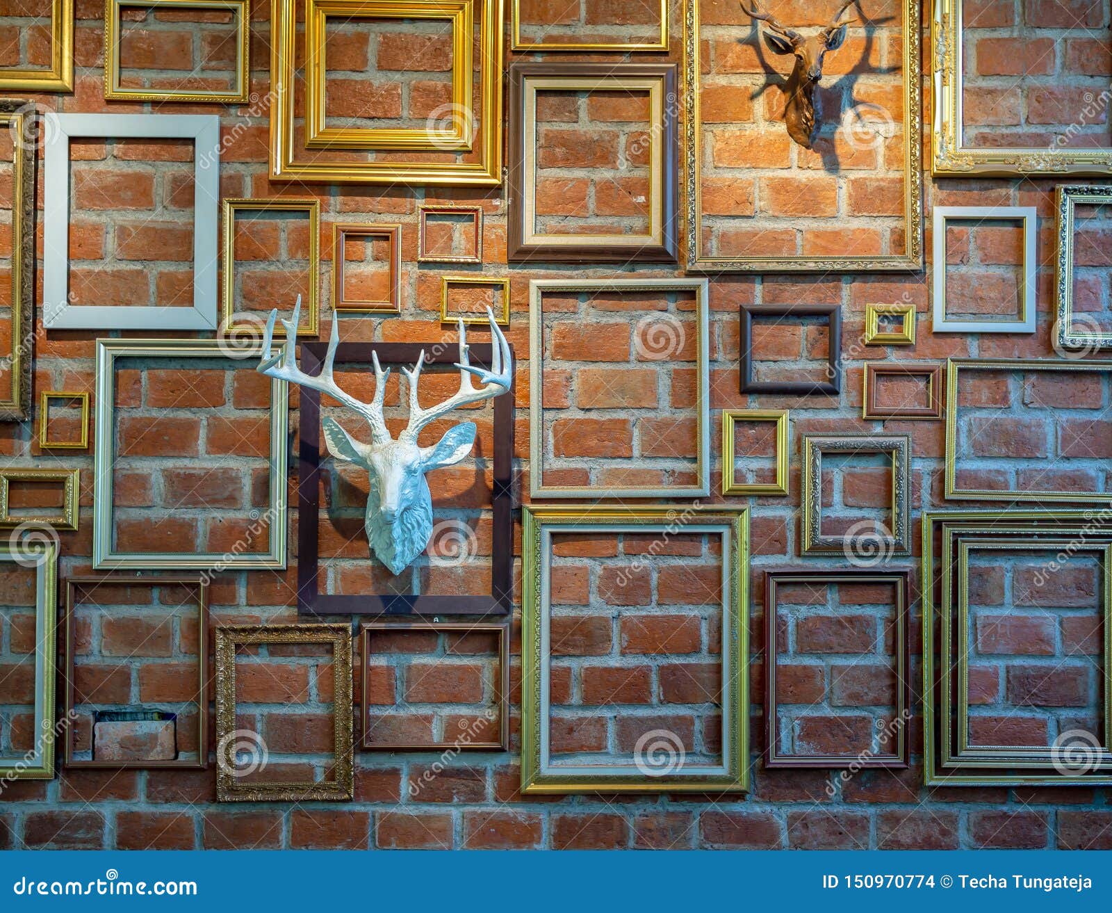 Various Empty Photo Frames with Plaster Deer Head Hanging on Brick Wall ...