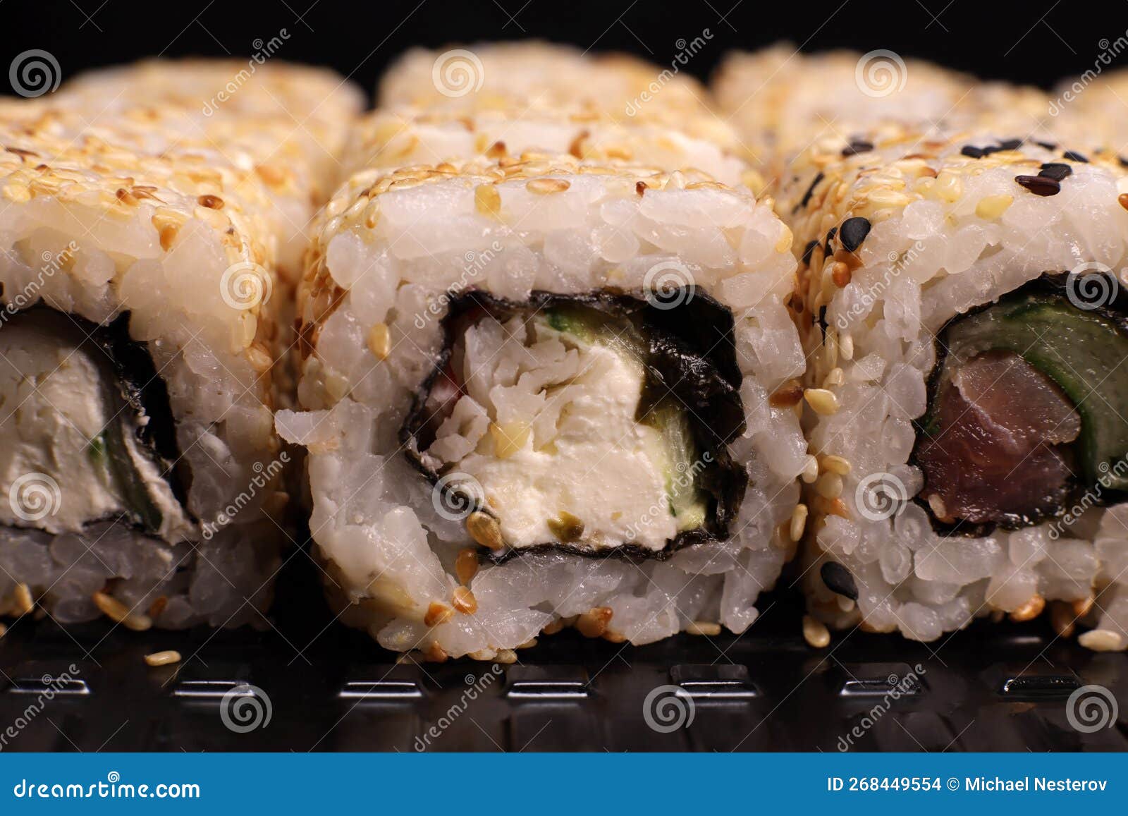 Various Sushi in a Row with Salmon, Tuna, Avocado, Sesame on a Mirror ...