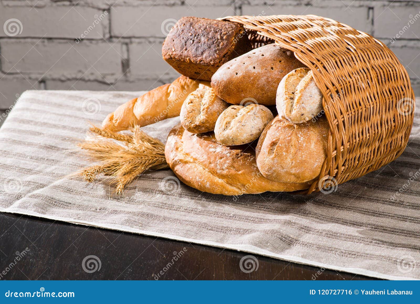 Various Types of Fresh Bread in a Basket on a Table, Brick Background ...