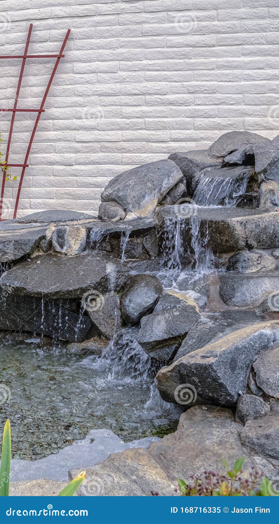Vertical Artificial Stone Cascade Waterfall in Backyard on a Sunny Day ...