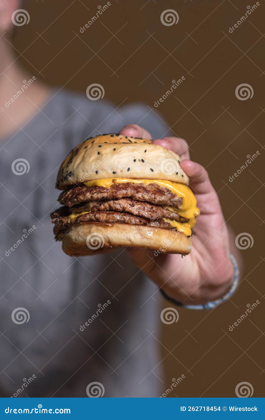 Vertical Closeup of a Cheeseburger Held by a Man Stock Photo - Image of ...