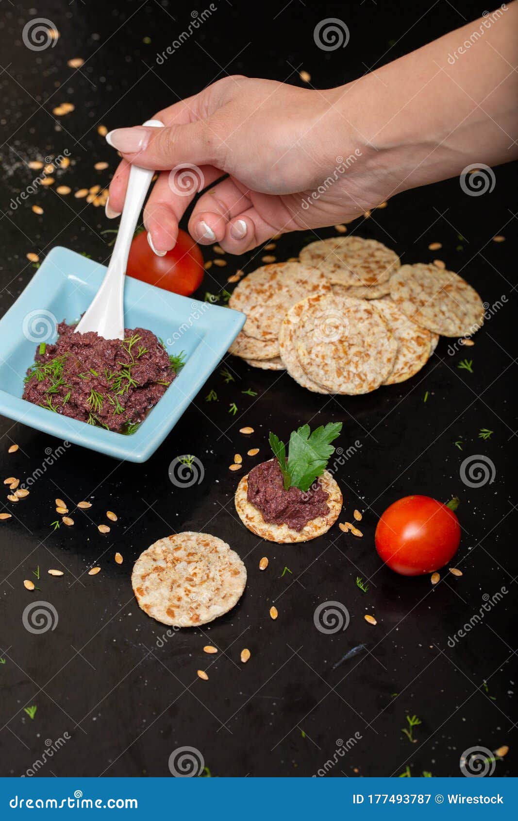 Vertical Closeup of a Person Putting Olive Paste on a Cracker Under the ...