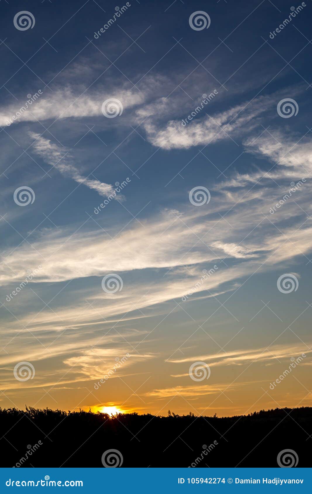 Vertical Cloudscape of Layered Clouds at Sunset with Sun Stock Photo ...