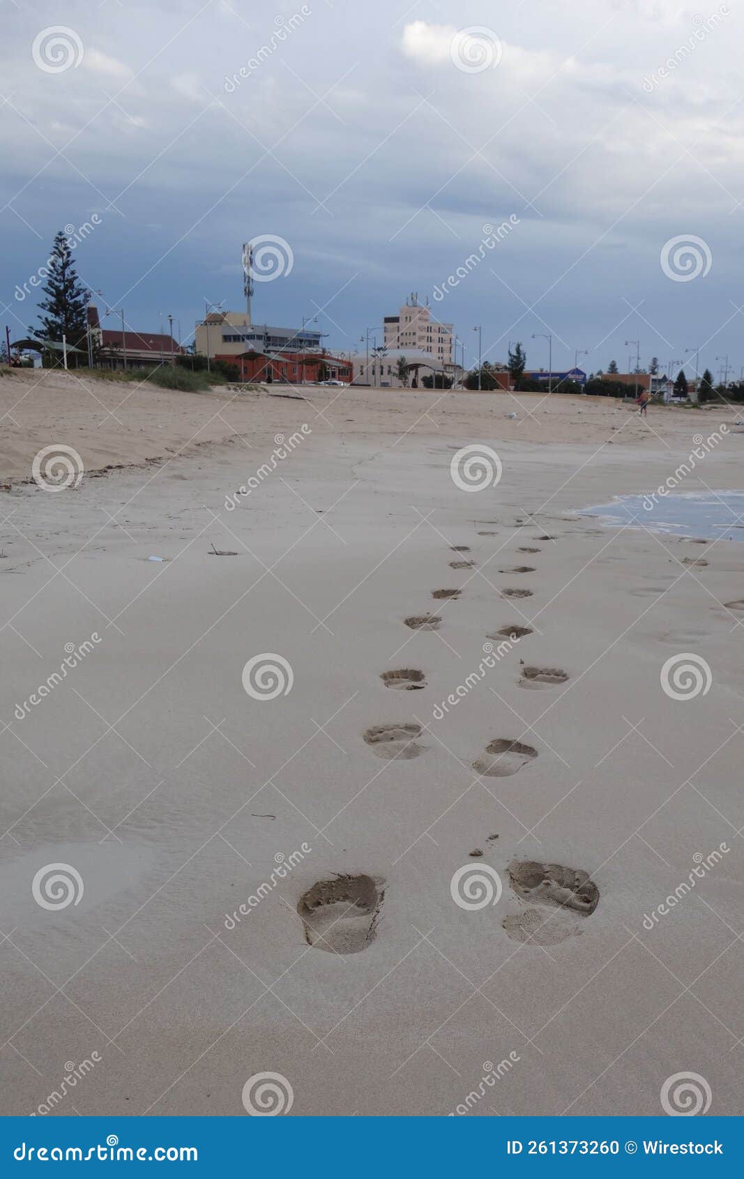 Vertical of Footprints on the Beach with Buildings in the Background ...