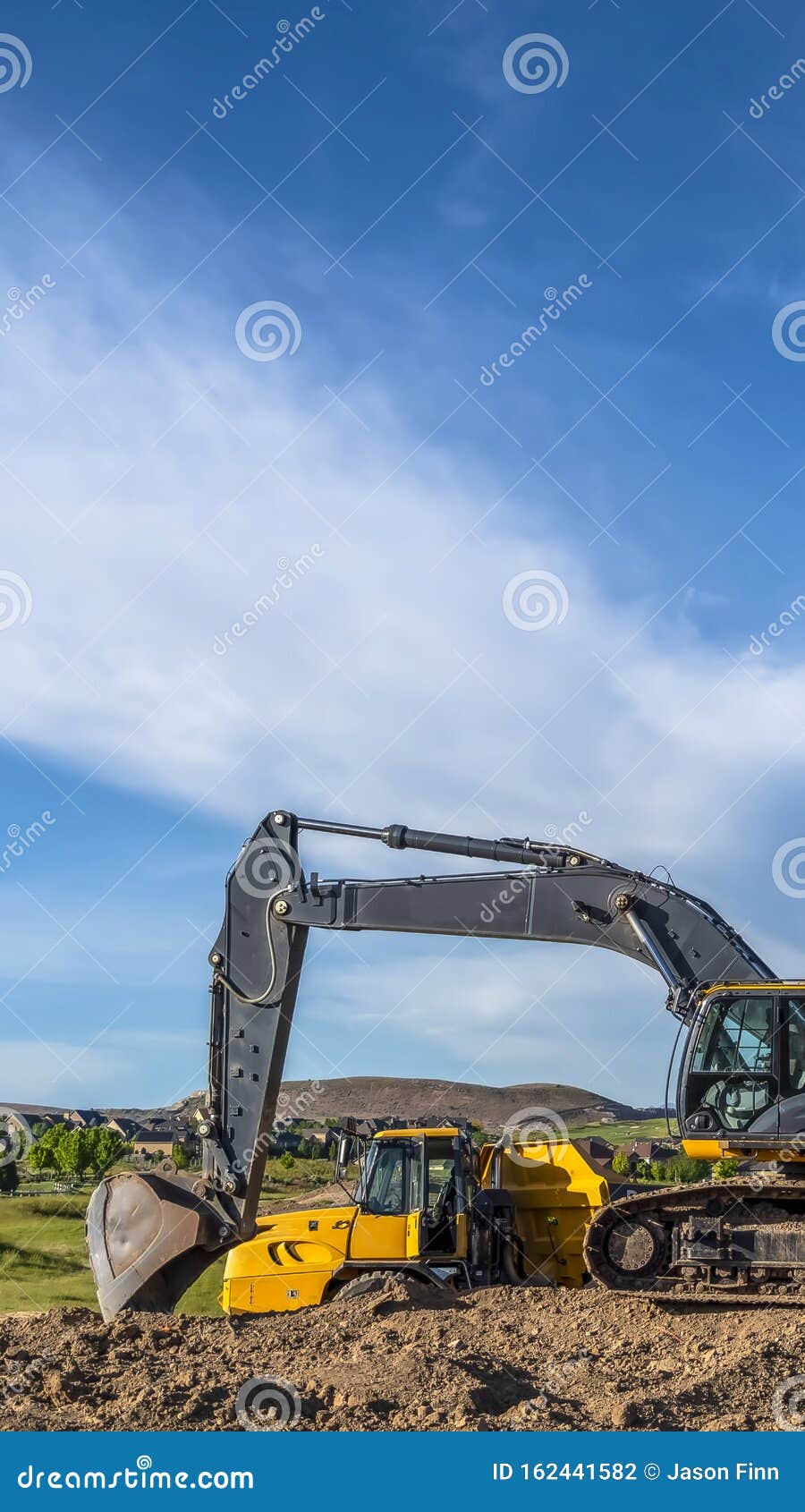 Vertical Frame Excavator at a Construction Site with Mountain Homes and ...