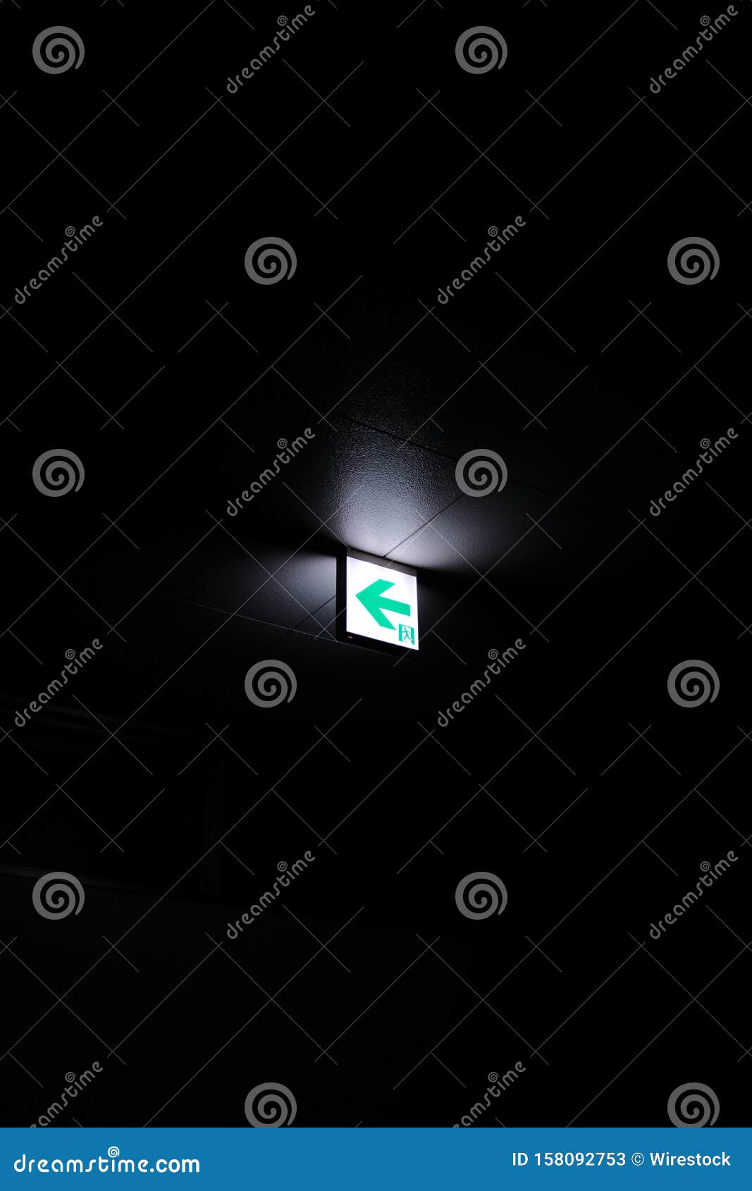 Vertical Grayscale Selective Focus Shot of a Lighted Green Exit Sign on ...