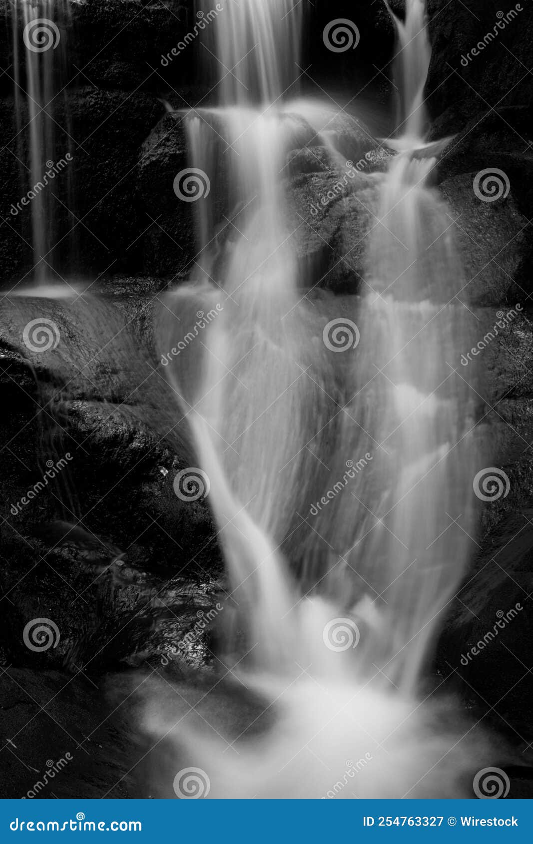 Vertical Grayscale Shot of a Beautiful Waterfall Surrounded by Rocks ...