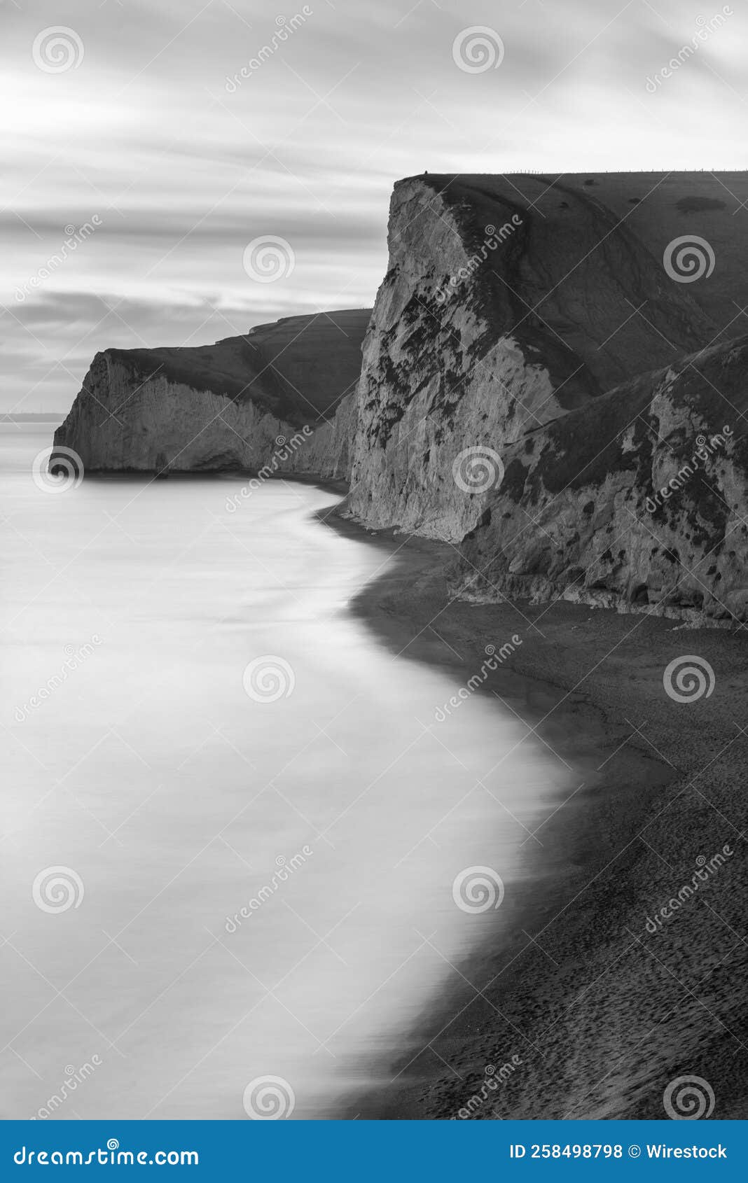 Vertical Grayscale of Waves Washing the Sandy Beach with Rocky Cliffs ...