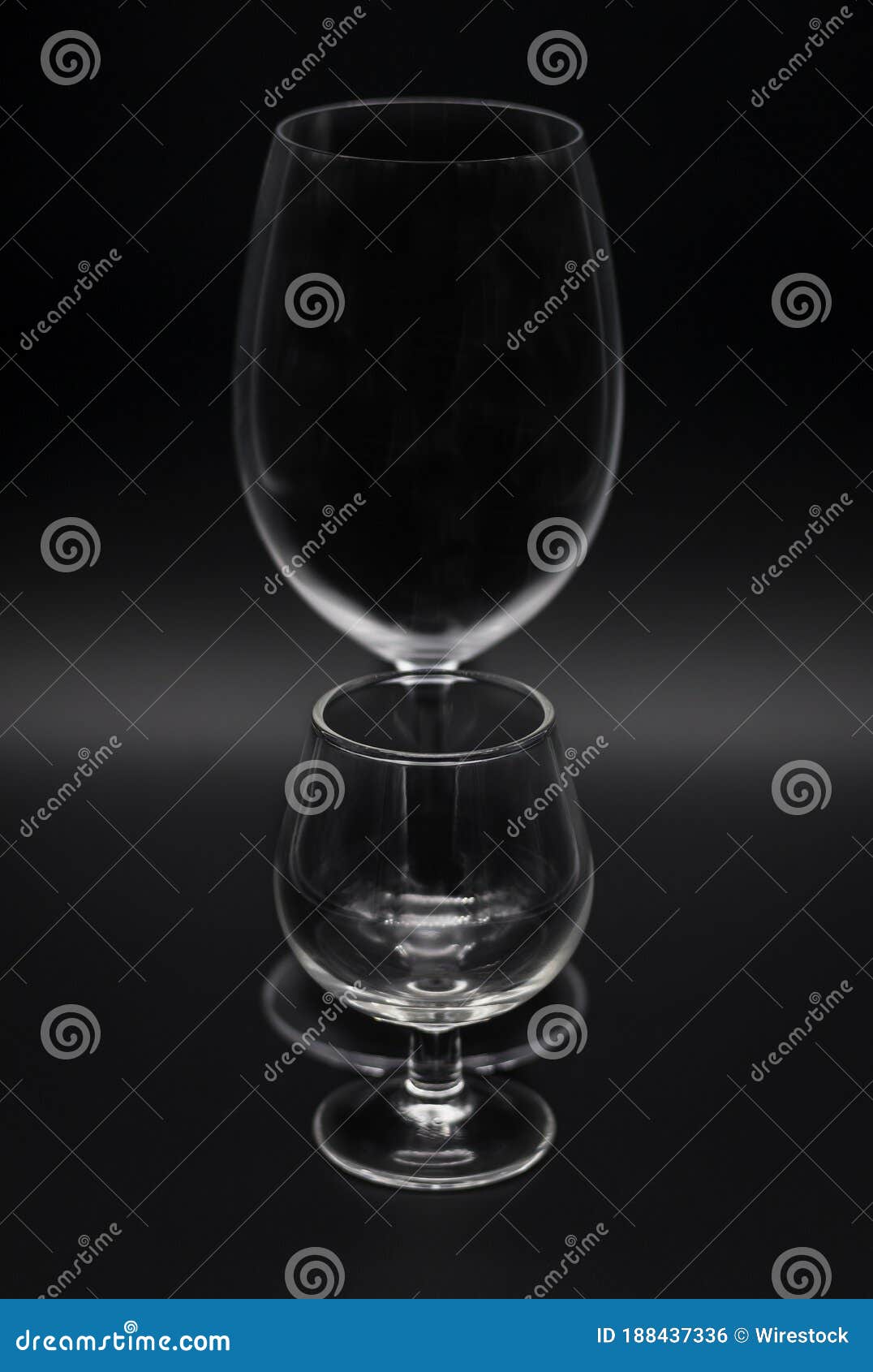 Vertical Greyscale Shot of Glass Cups with Reflections on a Black ...