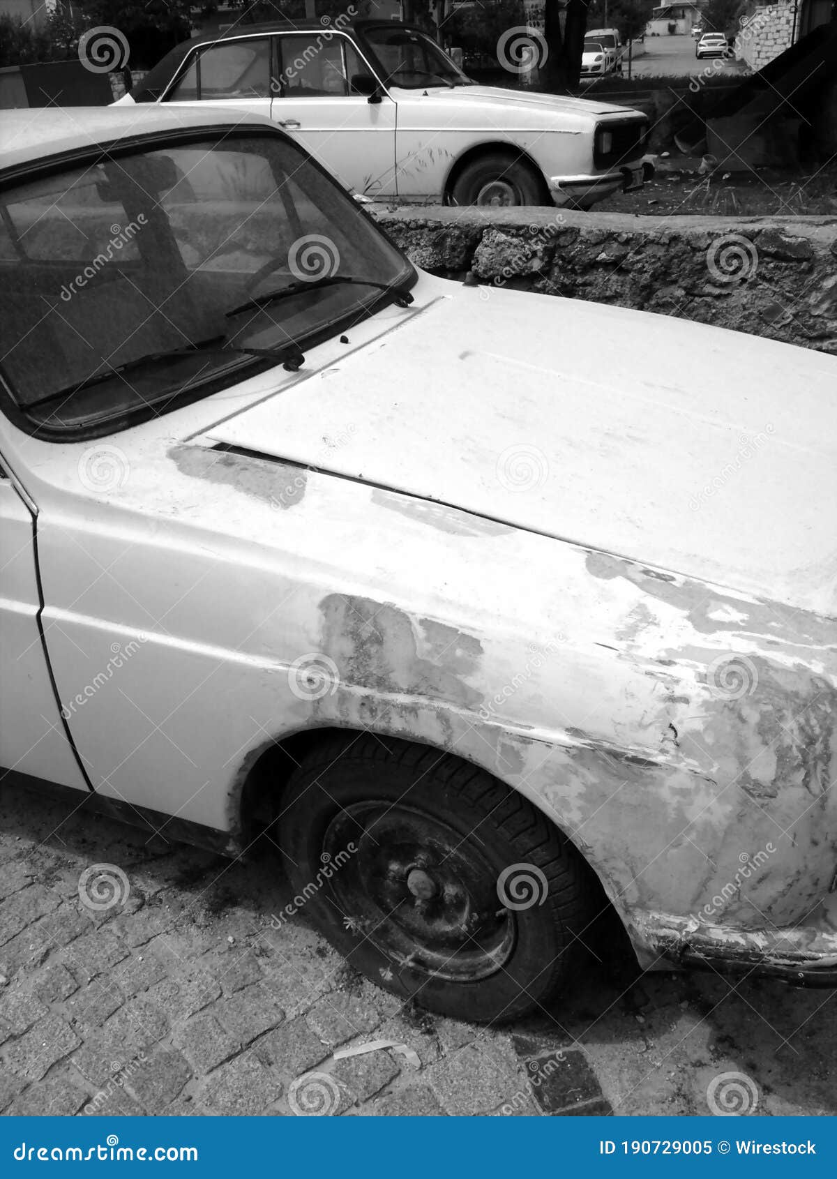 Vertical Greyscale Shot of an Old Rusty White Car in a Street Stock ...