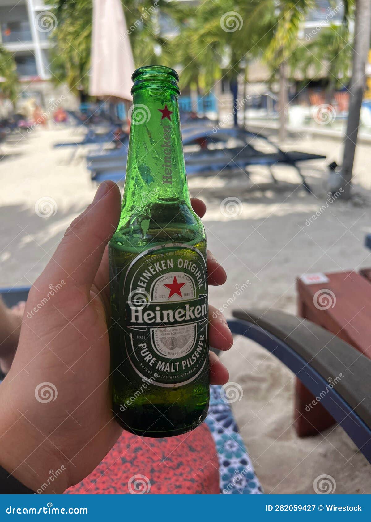 Vertical Of A Hand Holding A Bottle Of Heineken On The Beach Editorial ...