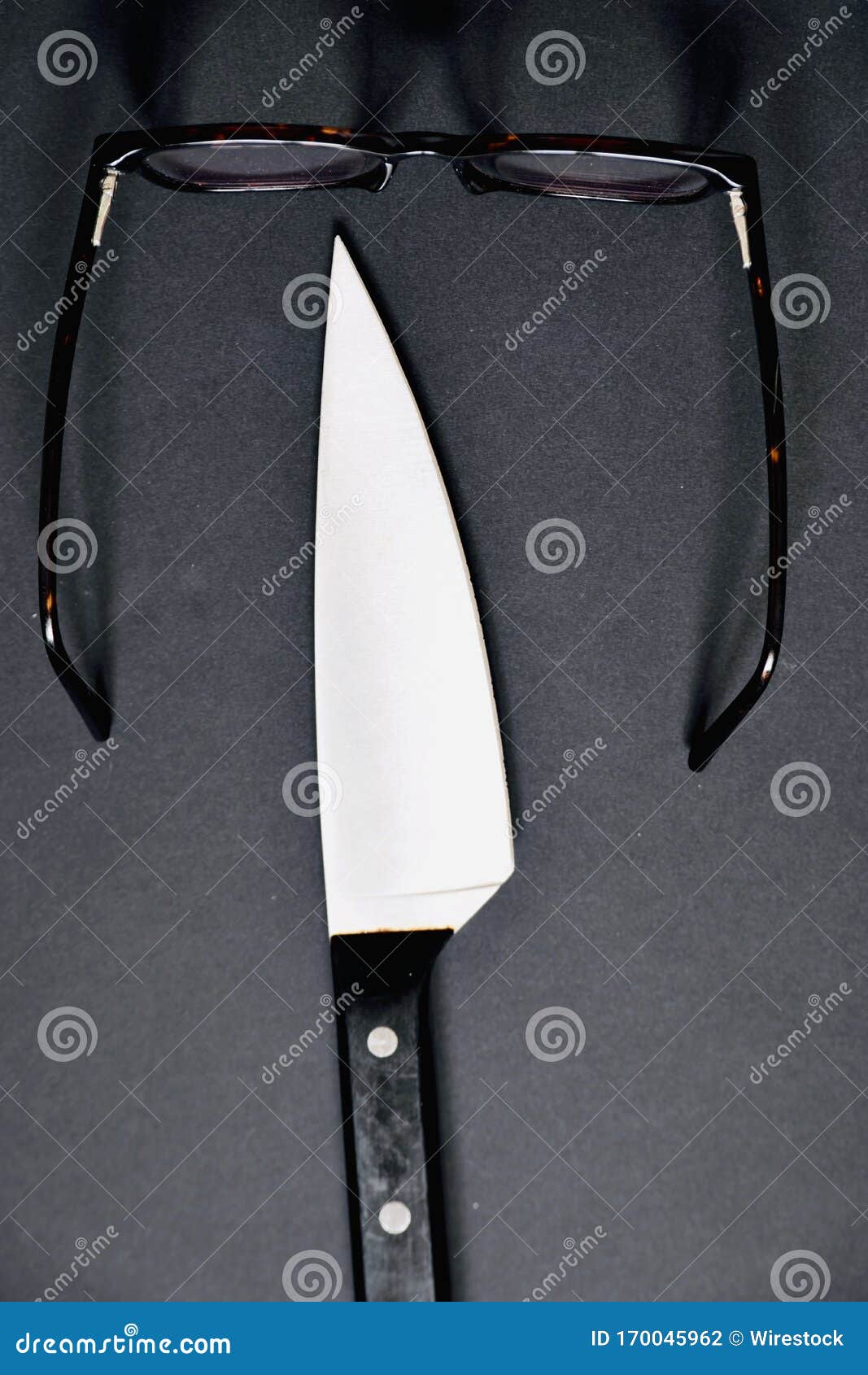 Vertical High Angle Shot of a Sharp Knife Next To a Brown Eyeglasses on ...