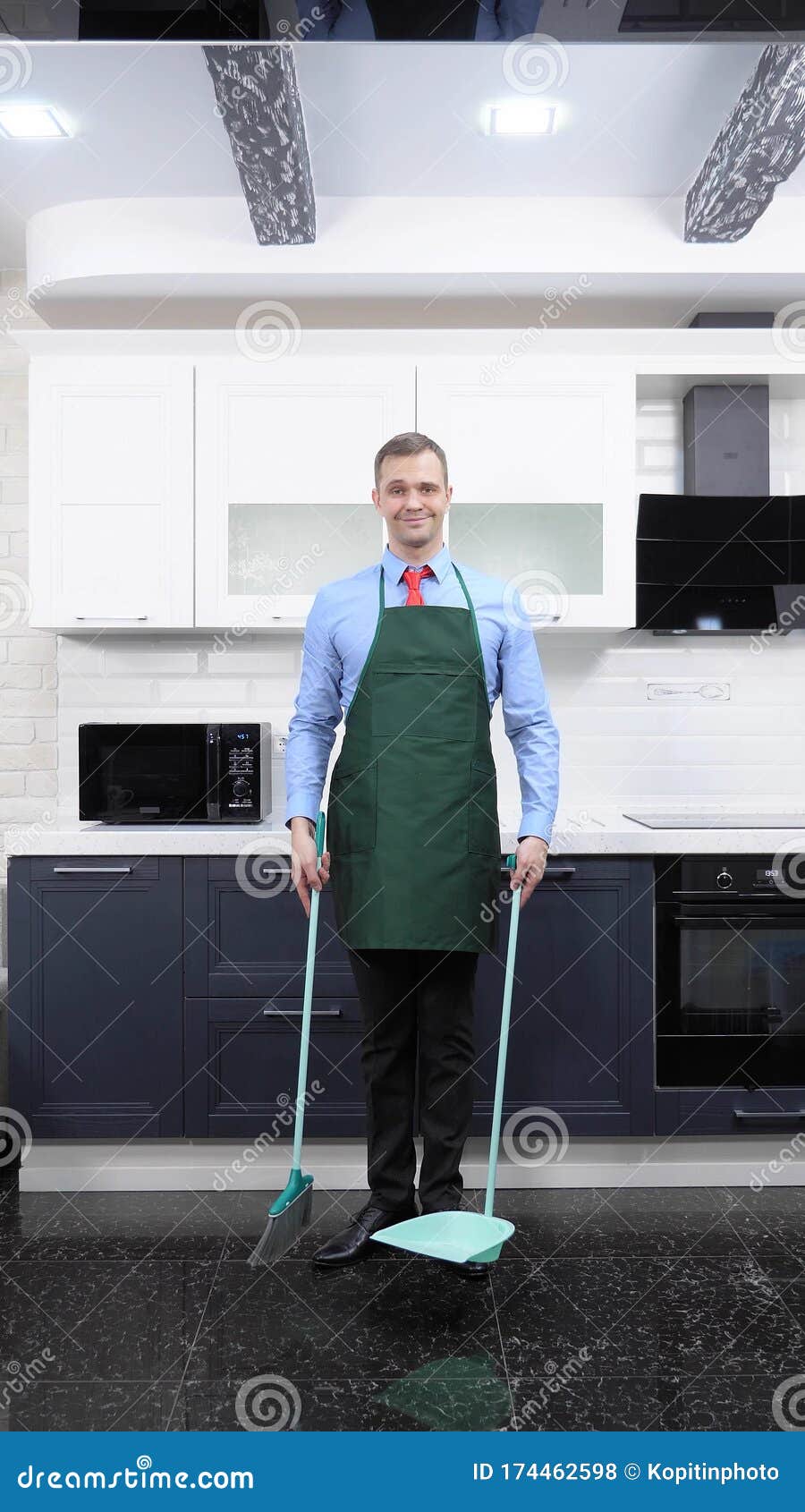 A Vertical Image. Handsome Man in Tie and Apron Sweeping the Kitchen ...