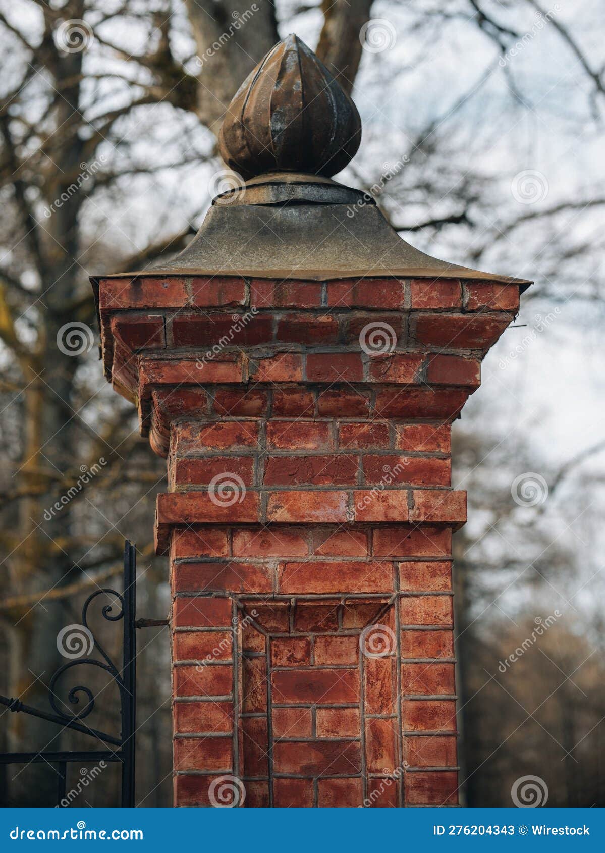 Vertical of Ornate Brick Pillar of a Gate Against Bare Trees Stock ...