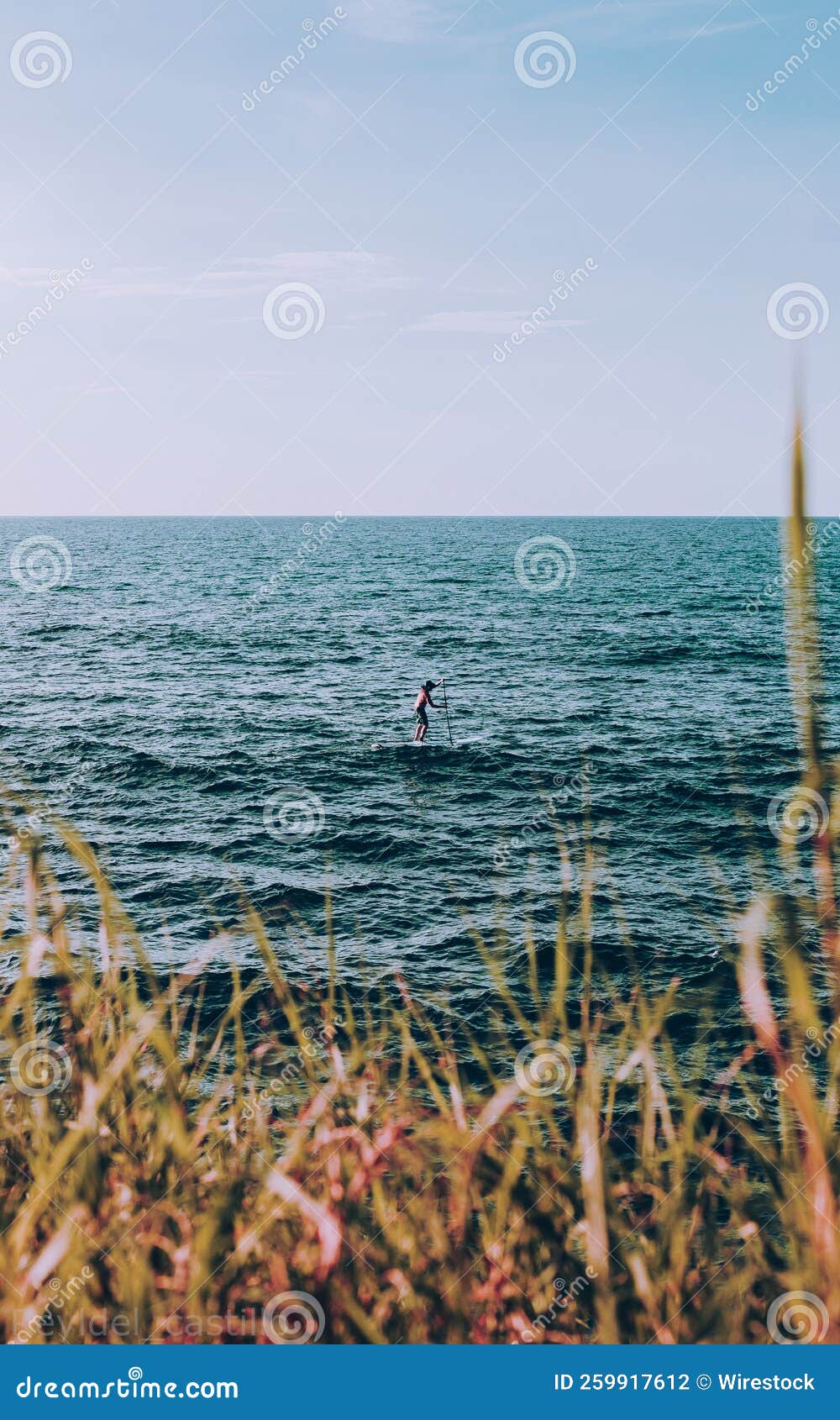 Vertical of a Person Surfing in the Distance in Ocean. Stock Photo ...
