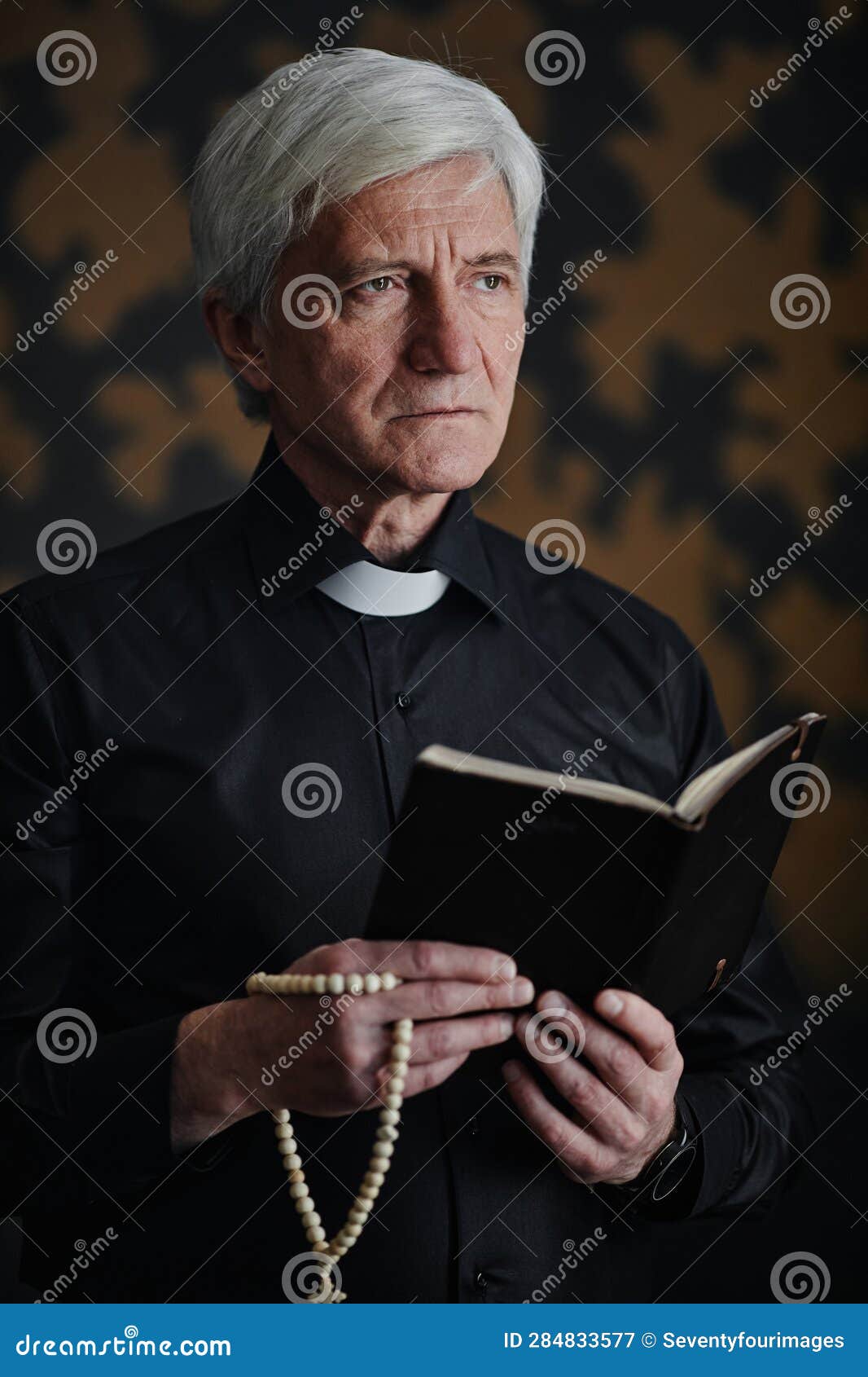 Vertical Serene Senior Priest Holding Bible in Dramatic Lighting Stock ...