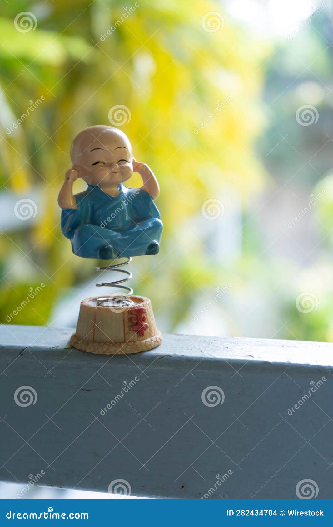 Vertical Selective Focus Shot of a Cute Praying Monk Spring Figurine on ...