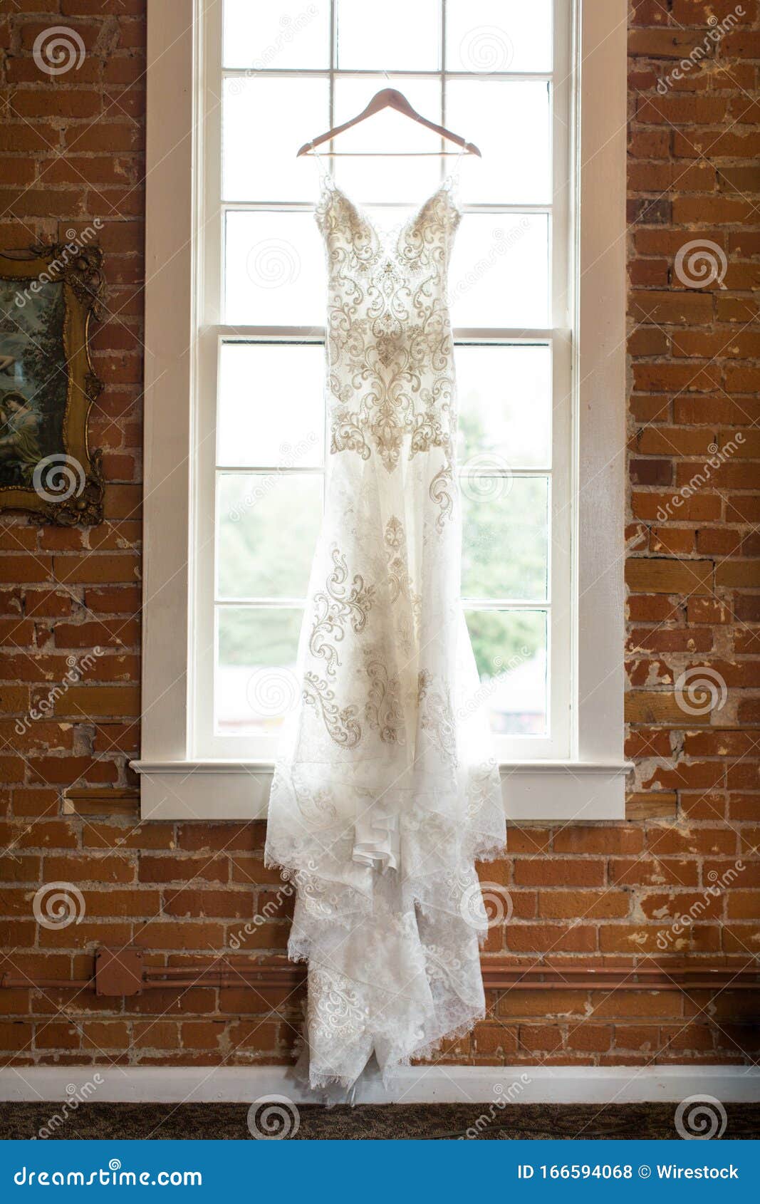 Vertical Shot of Beautiful White Wedding Drees Hung Near the Window ...