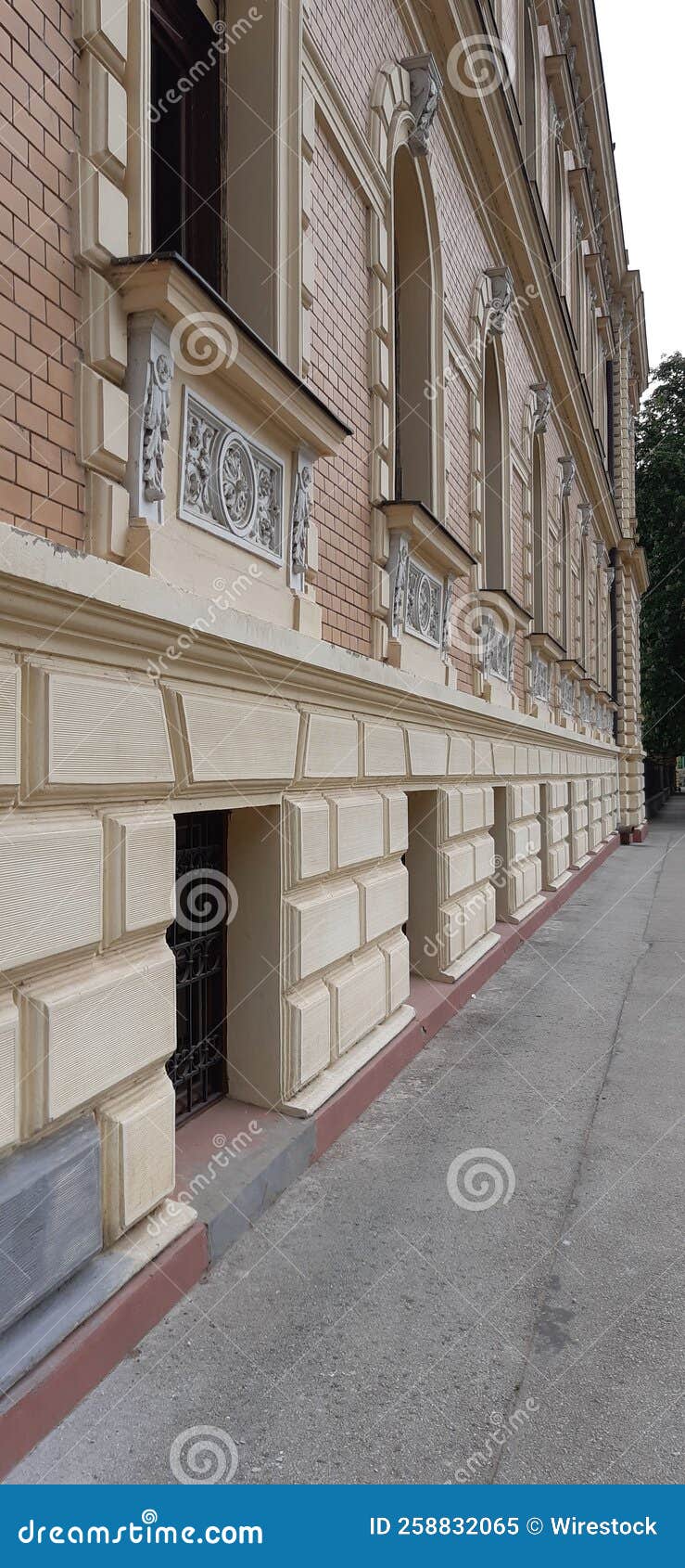 Vertical Shot of the Brick Wall of a Building with Windows and a Paved ...