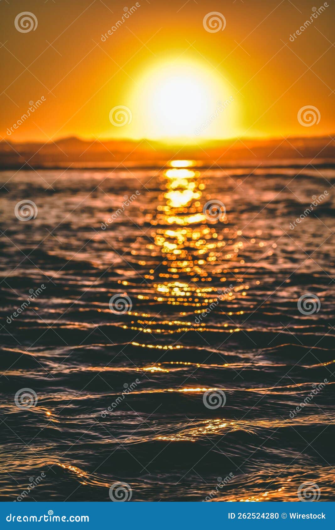Vertical Shot of a Bright Sunset Sun Reflected on Calm Ocean during a ...