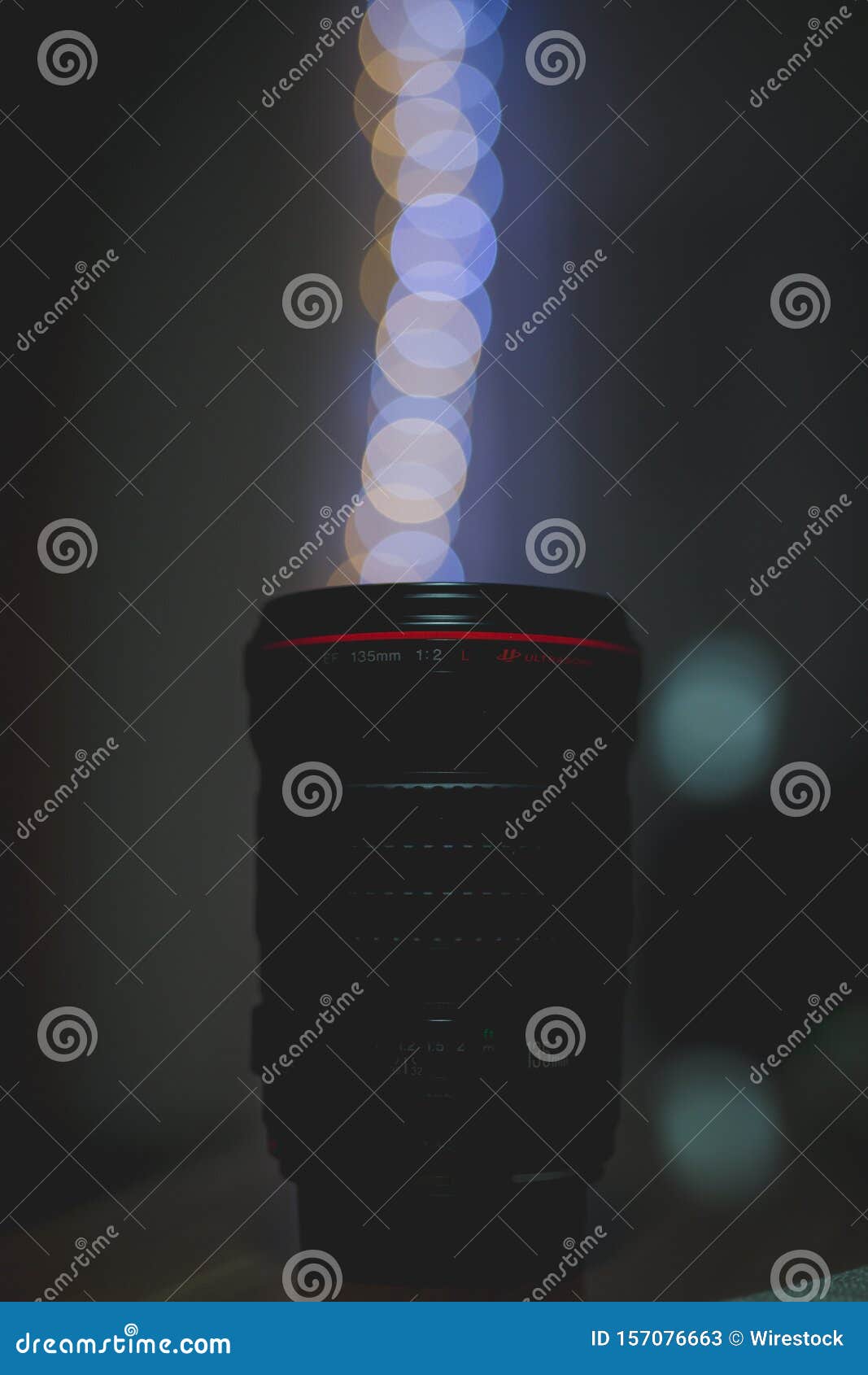 Vertical Shot of a Camera Lens with Blurred Lights in the Background ...