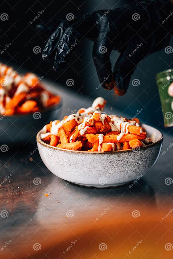 Vertical Shot of a Cook Sprinkling Pepper on Fried Food on the Table ... Vertical Shot of a Cook Sprinkling Pepper on Fried Food on the Table ...