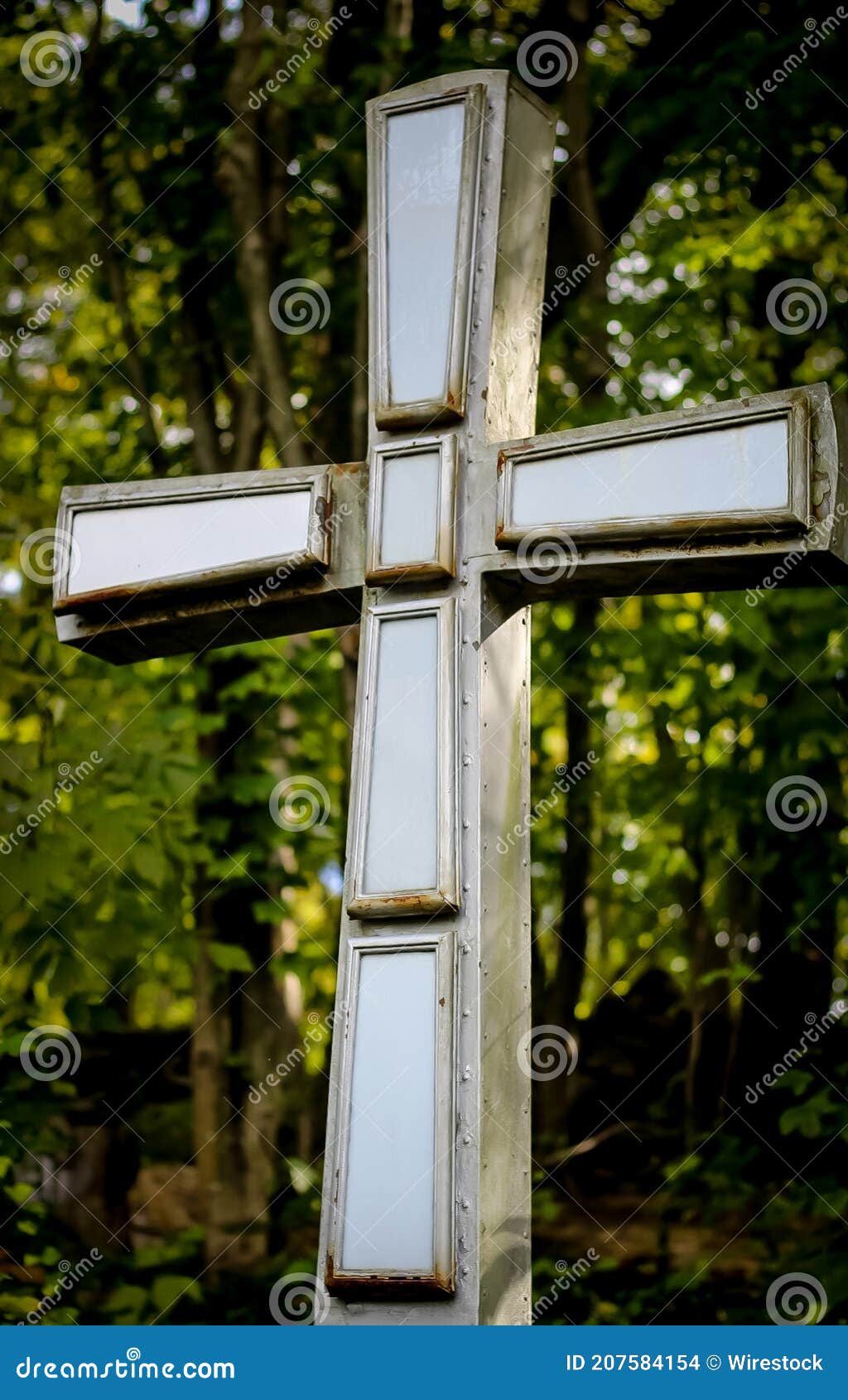Vertical Shot of a Cross Surrounded by Trees in a Garden Under the ...