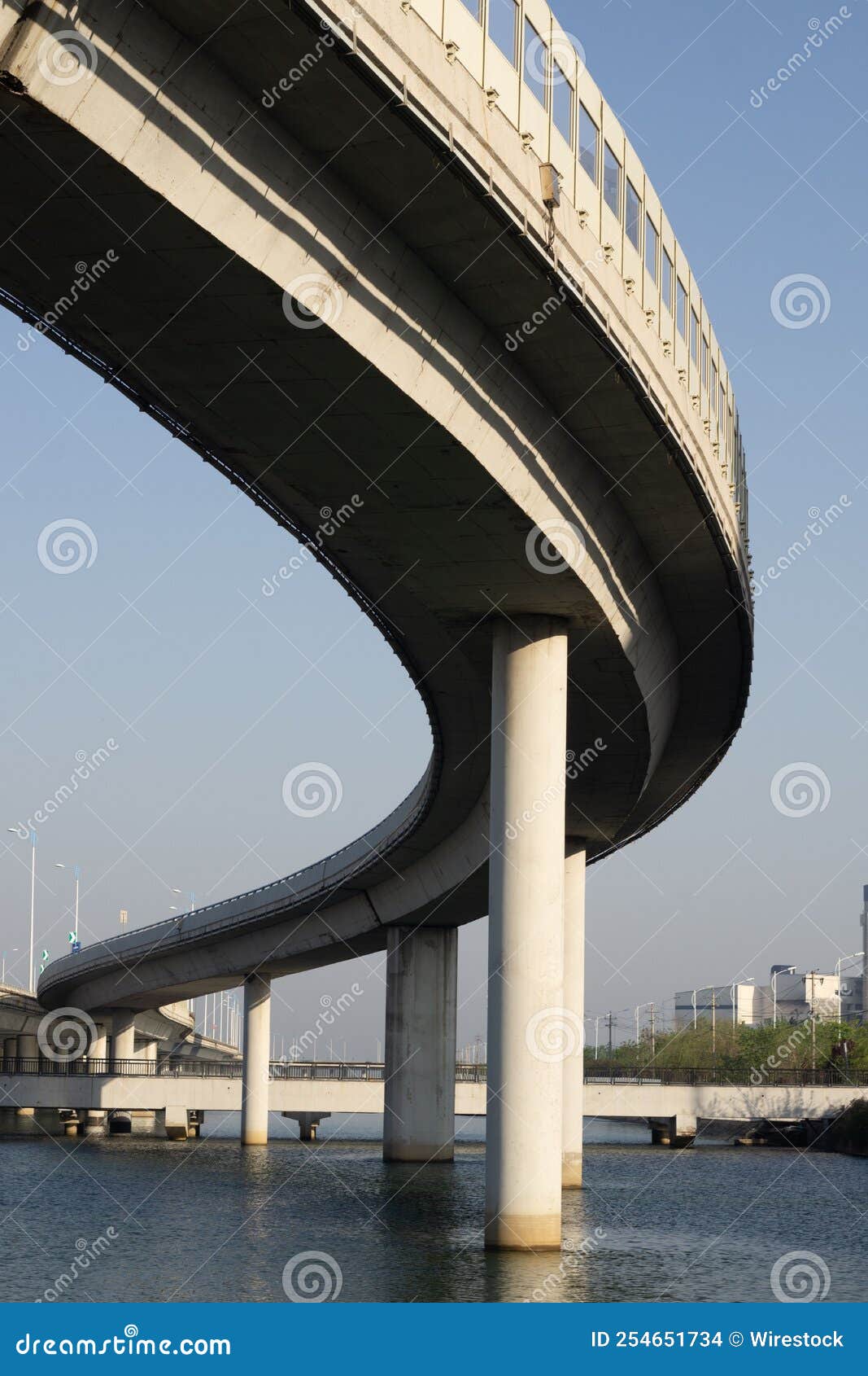 Vertical Shot of a Curved Bridge on Water with a Blue Skyscape in the ...