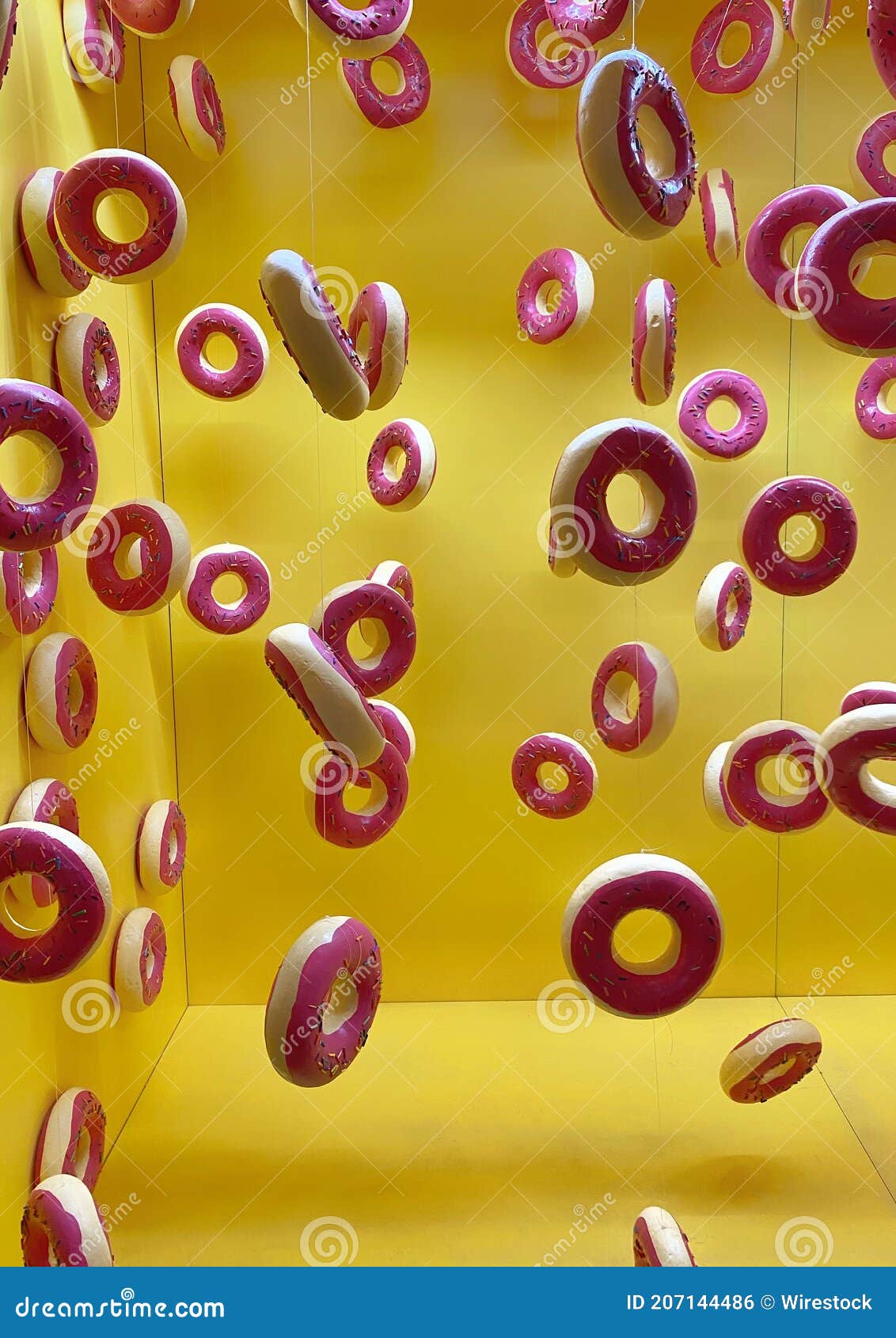Vertical Shot of Donut Figures Hanging from Ropes in a Yellow Room ...