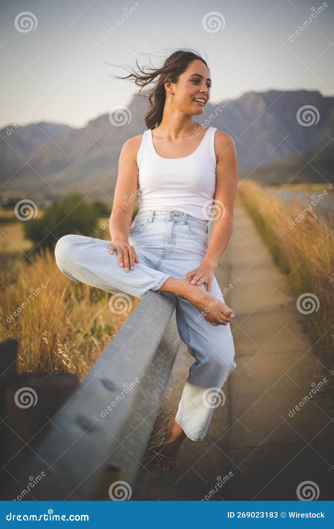 Vertical Shot Of Happy Caucasian Female In Light Blue Jeans White Top