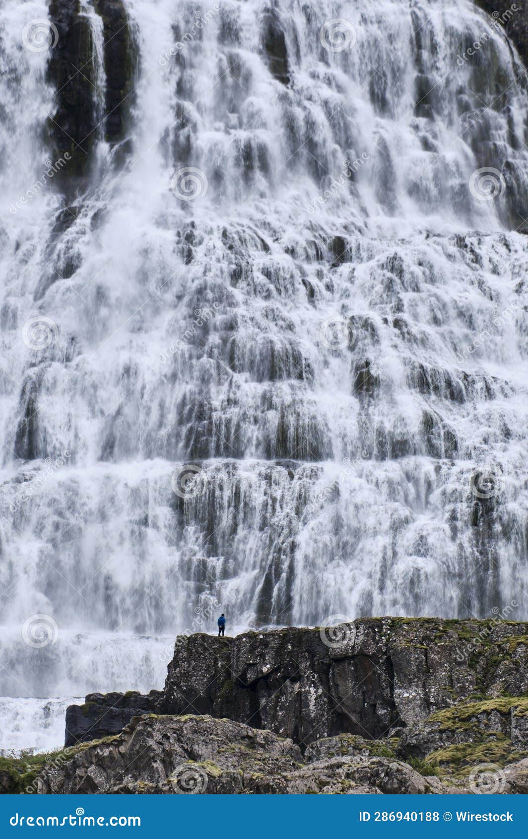 Vertical Shot of the Majestic Diyandi Waterfall with a Person Standing ...