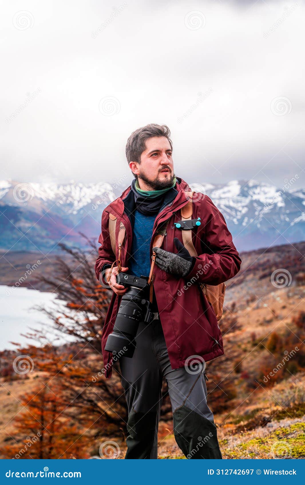 Vertical Shot of a Man with a Camera on a Mountaintop, Surrounded by ...