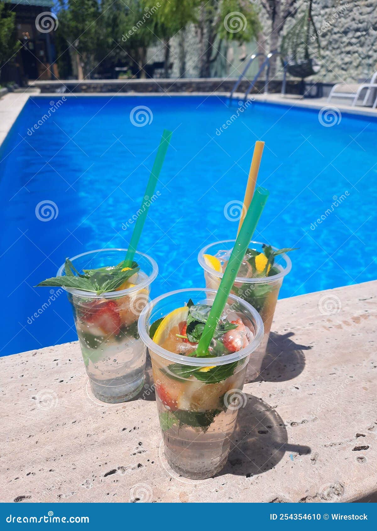 Vertical Shot of Mojito Cocktails by a Pool with Trees in the ...