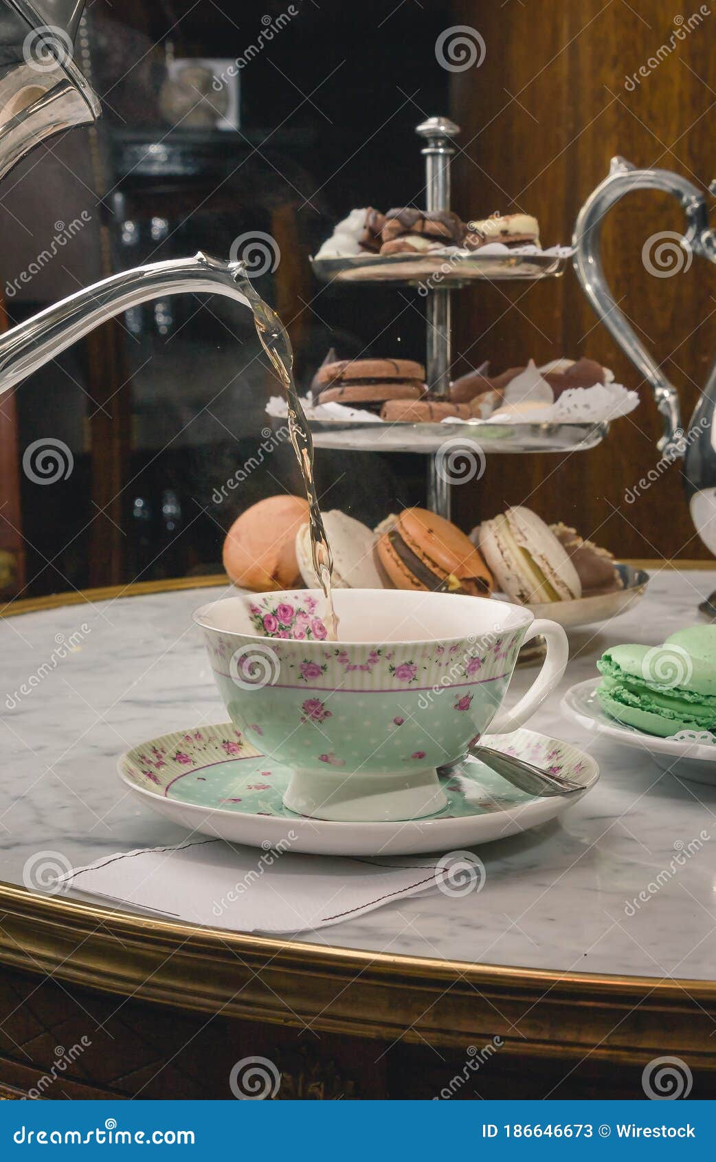 Vertical Shot of a Pouring Tea in a Cup on a Marble Table with Desserts ...