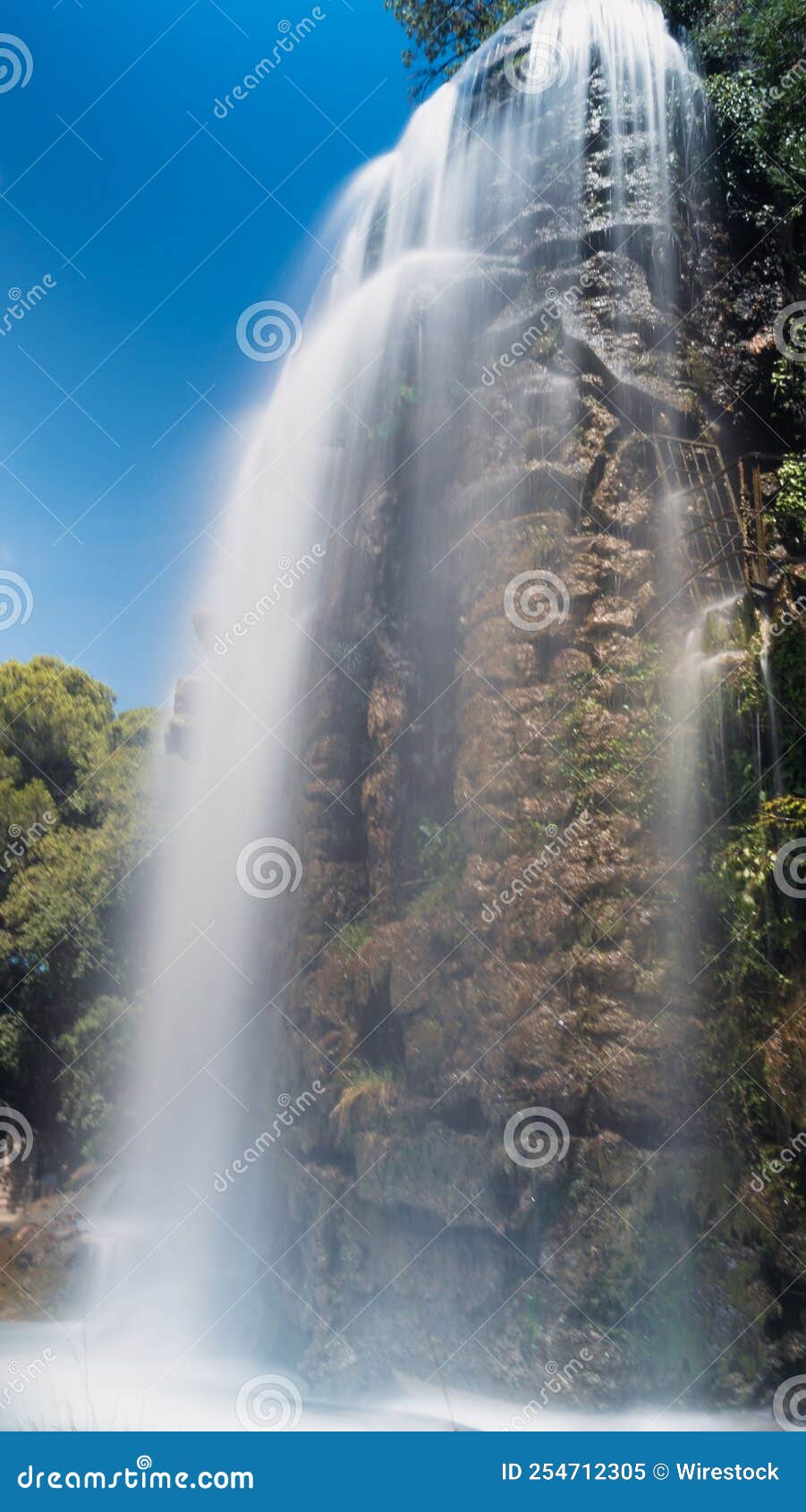 Vertical Shot of a Scenic Waterfall Going Down the Rocks with a Blue ...