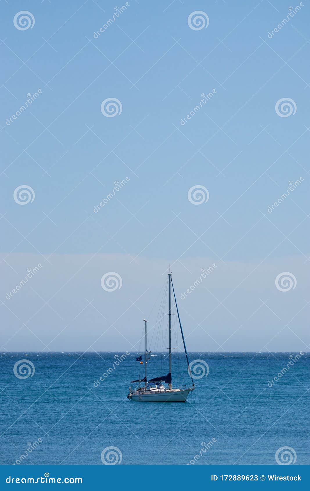 Vertical Shot of a Small Boat Sailing in the Ocean with a Clear Blue ...