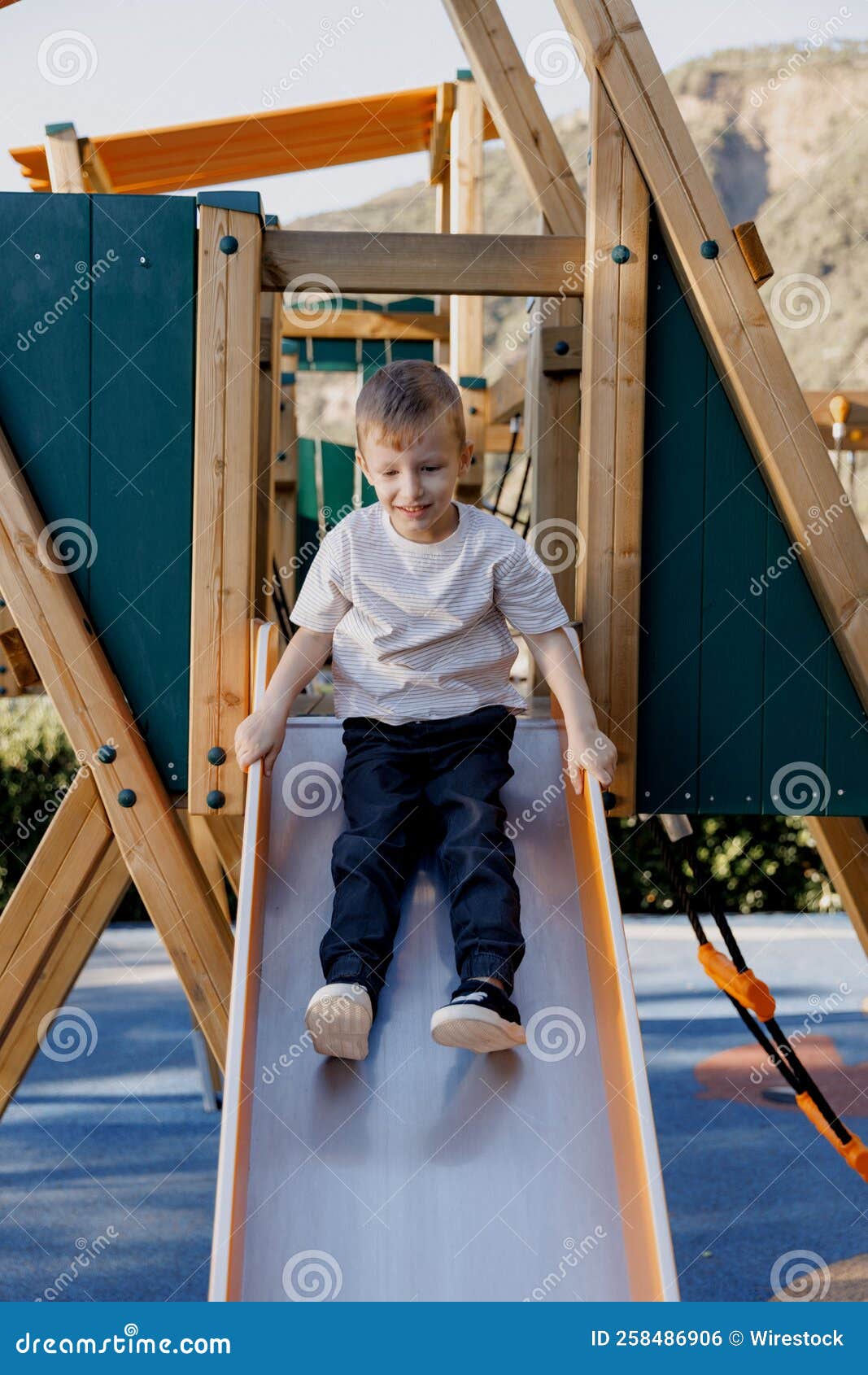 Vertical Shot of a Smiling Boy Going Down the Slide in a Playground ...