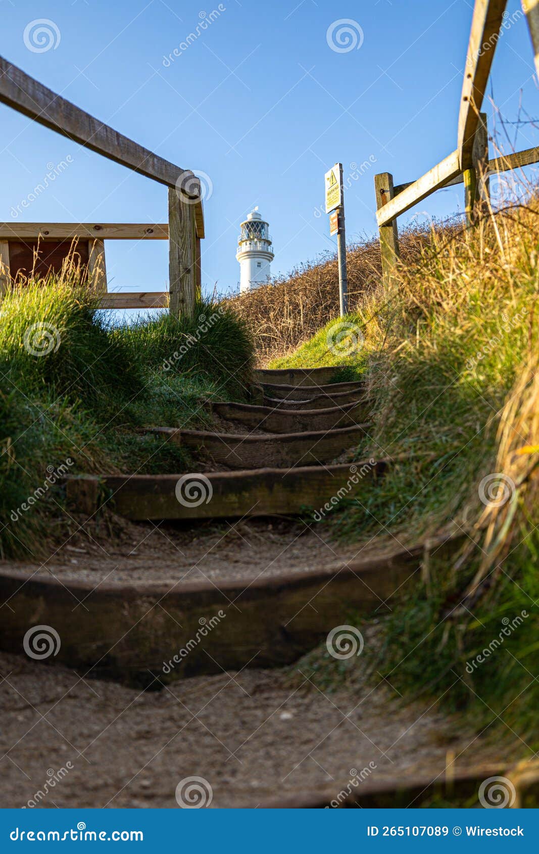 Vertical Shot of Stairs Leading Toward a Lighthouse Under a Blue Sky ...