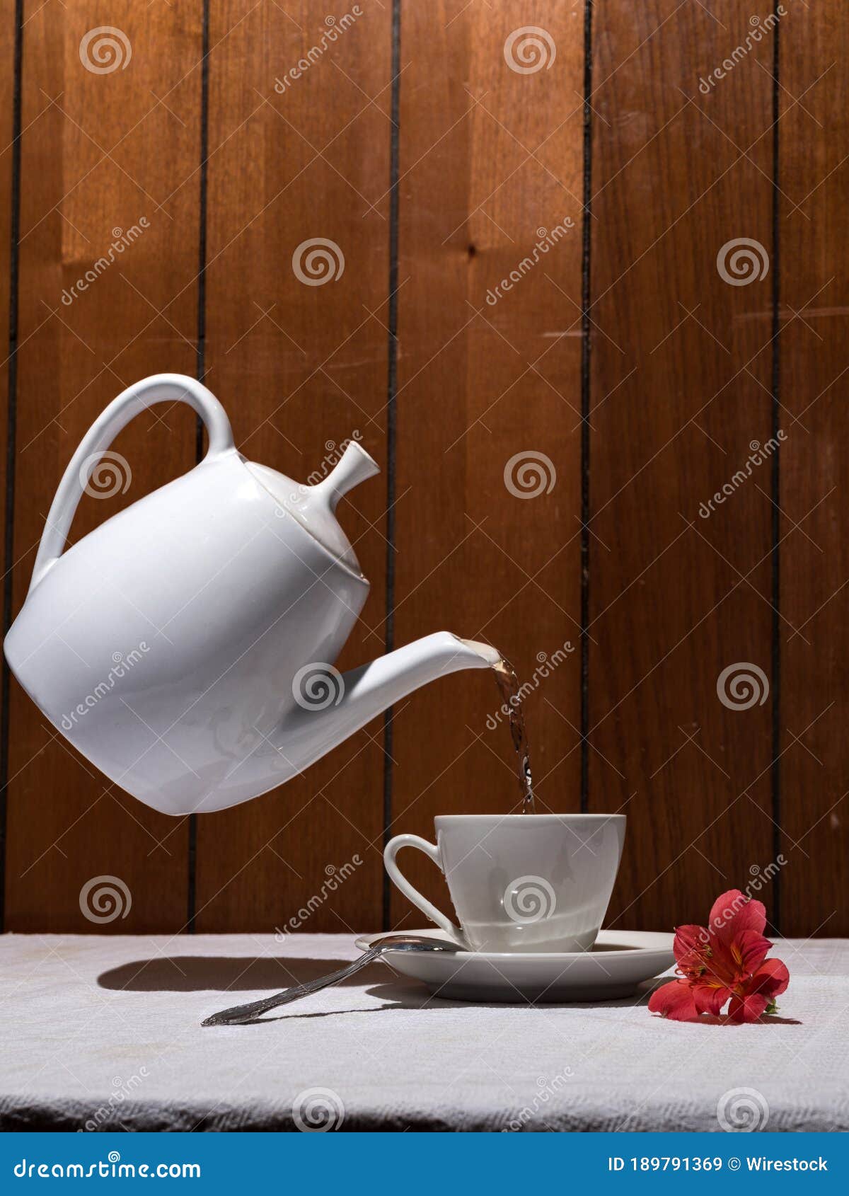 Vertical Shot of Tea Pouring from a Teapot into a Cup on the Table ...