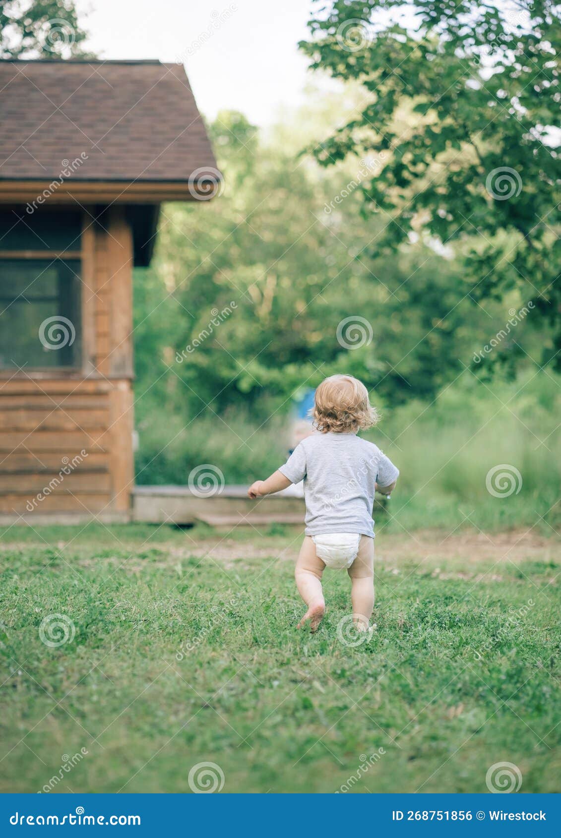 Vertical Shot of a Toddler in Diapers Running in the Backyard Stock ...