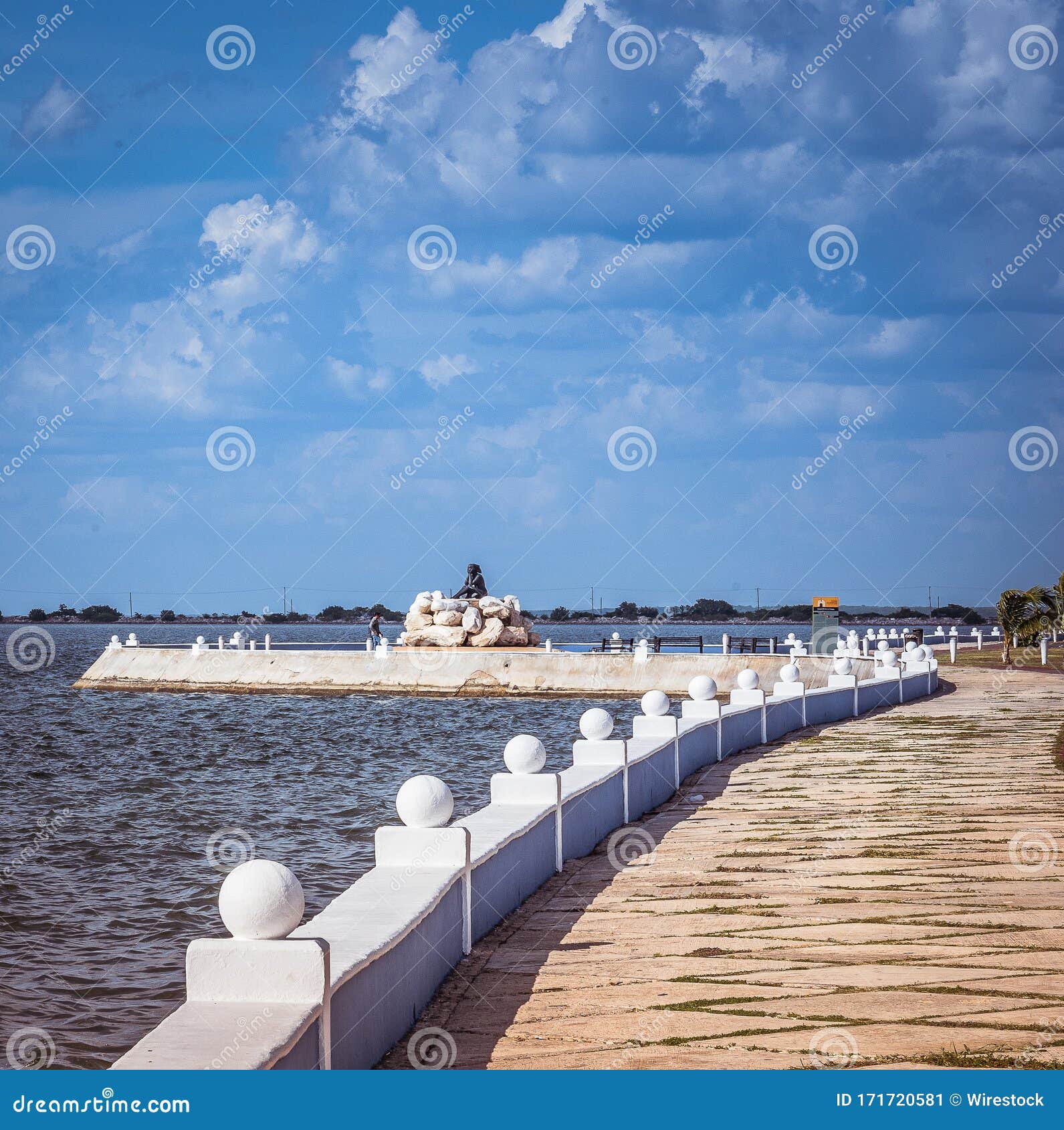 Vertical Shot of a Walkway Around the Ocean Under a Blue Sky Full of ...