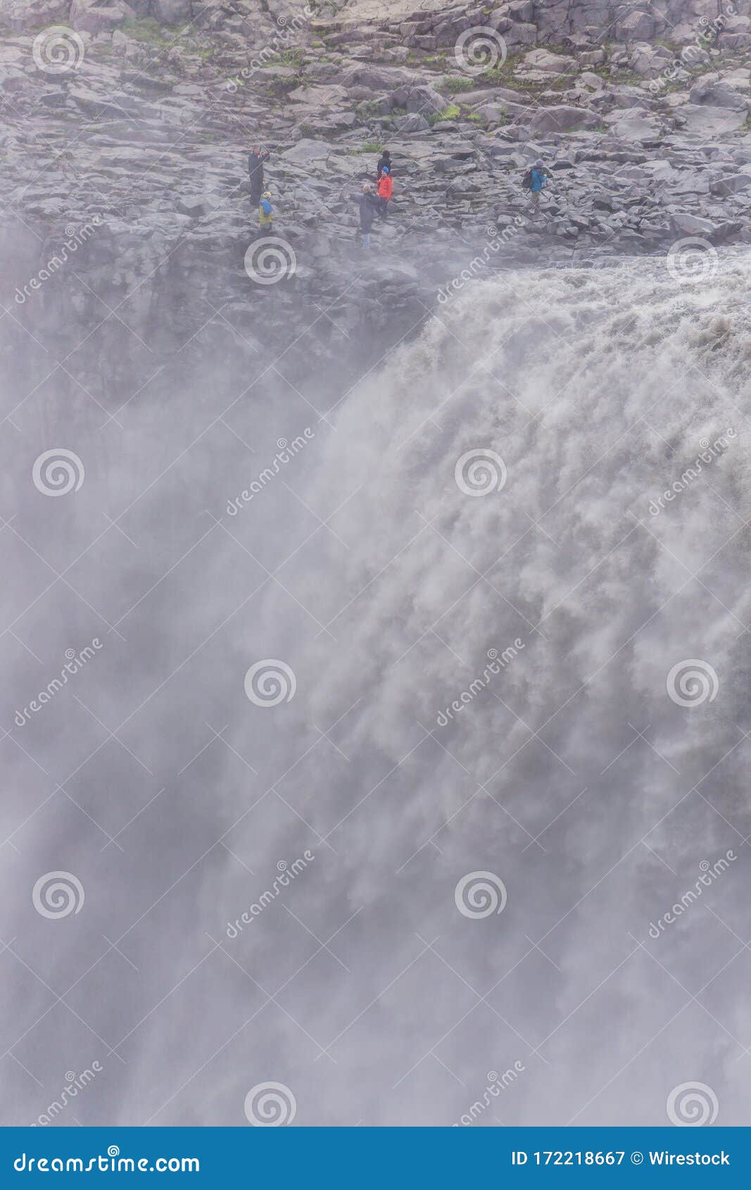 Vertical Shot of a Waterfall with People Standing in the Distance ...