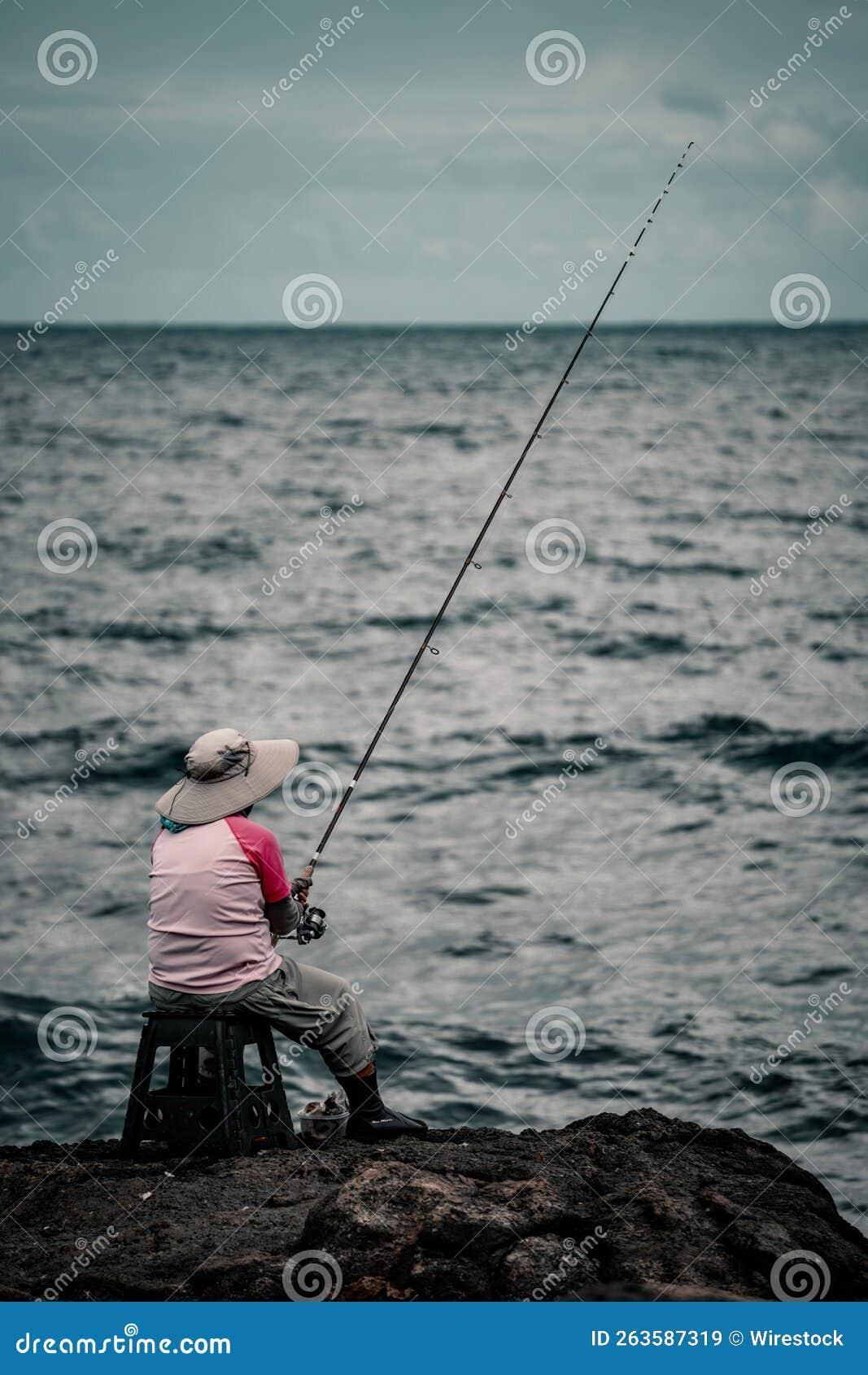 Vertical Shot of a Woman Sitting on a Chair and Catching Fish with a ... Vertical Shot of a Woman Sitting on a Chair and Catching Fish with a ...