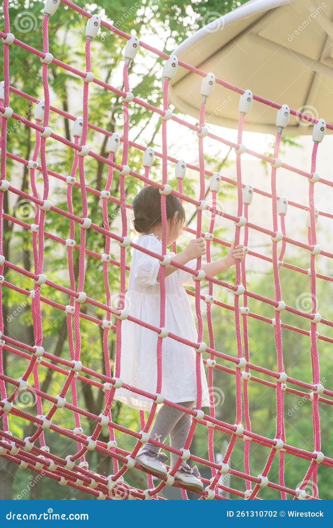 Vertical Shot of a Young Girl Playing in the Playground Monkey Ropes ...