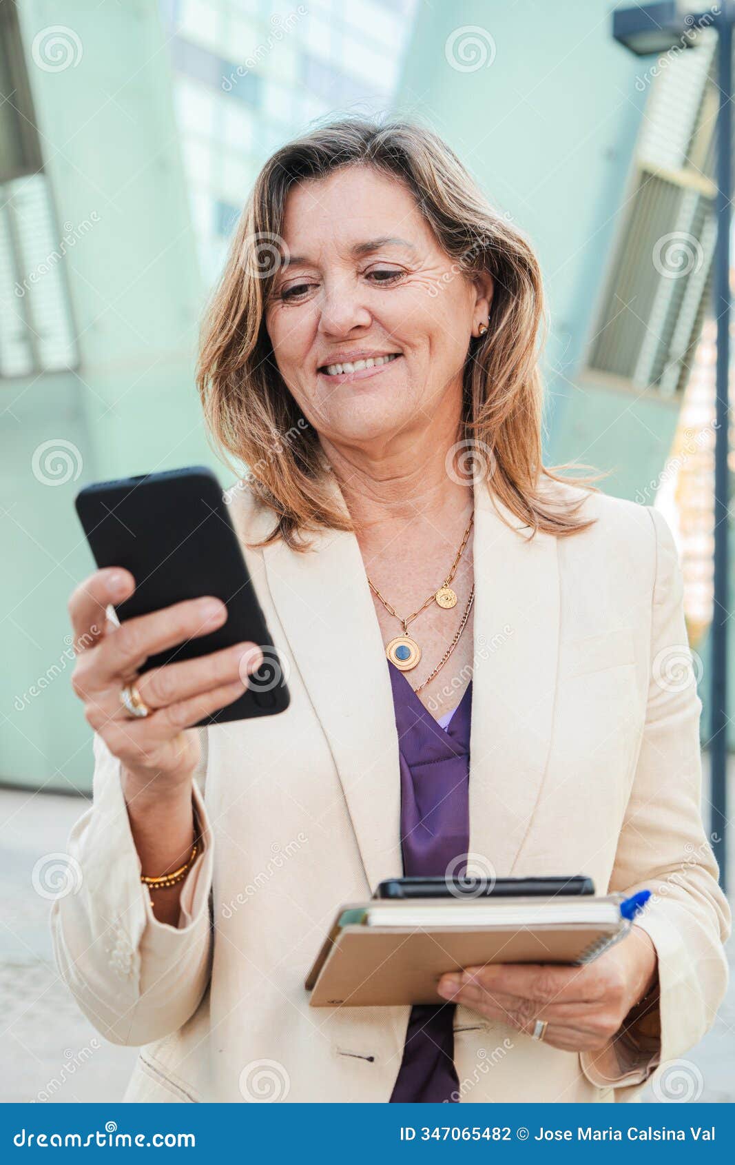 Vertical. Smiling Mature Lady Using a Cellphone Outdoors, Dressed in ...